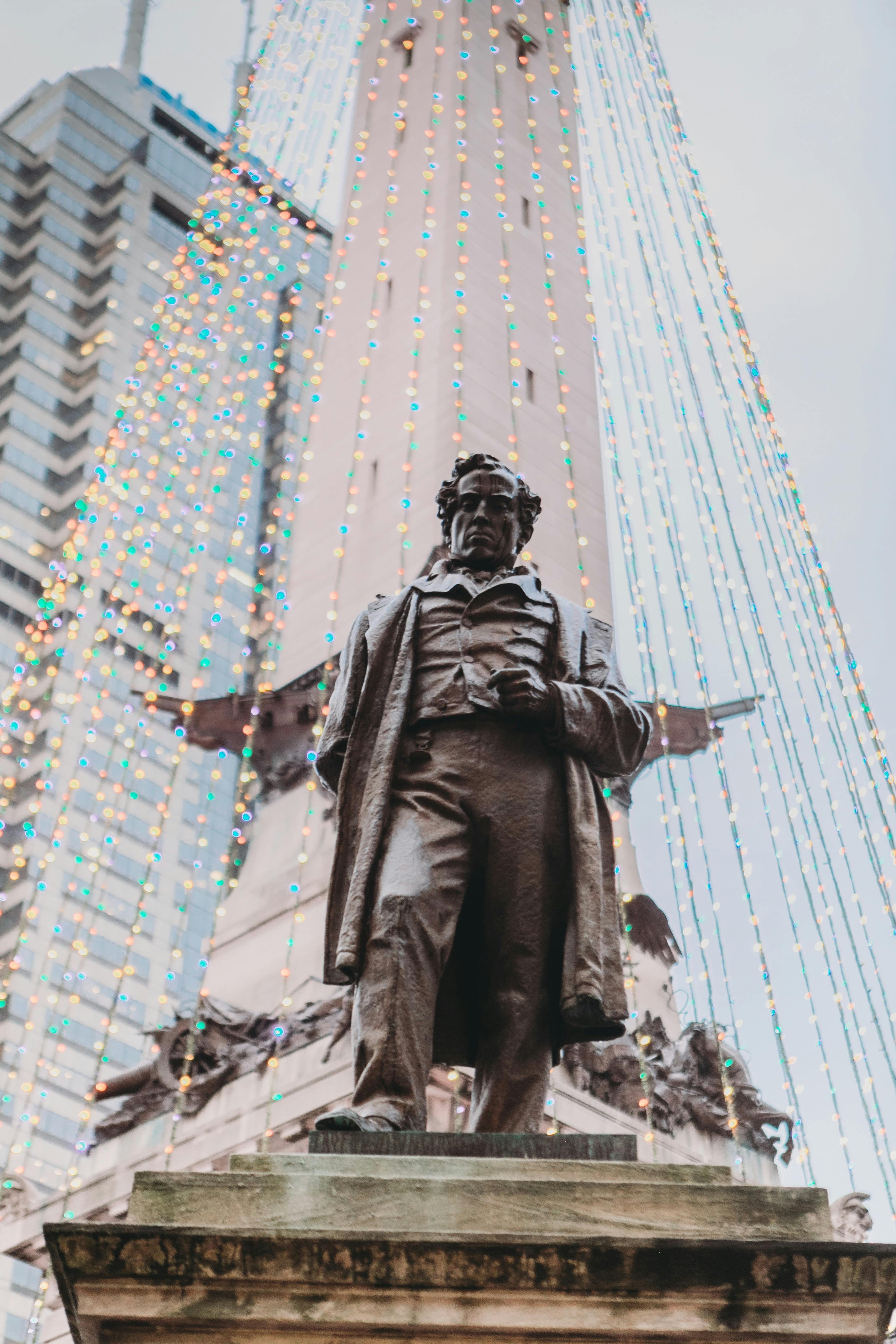 Statue under Fairy Lights near Glass Building · Free Stock Photo