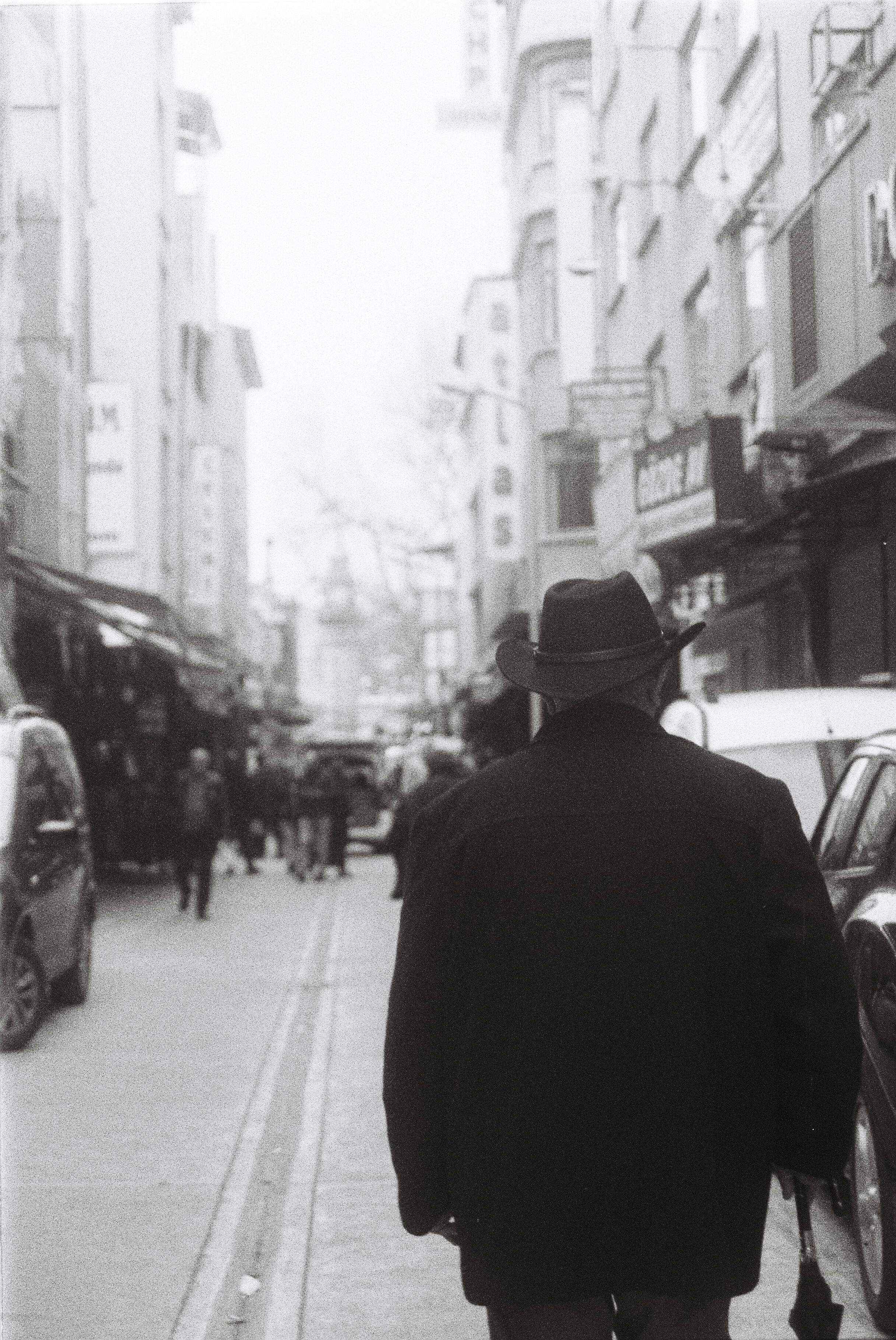 Back View of a Man in a Hat Walking on a Crowded Street in City · Free ...