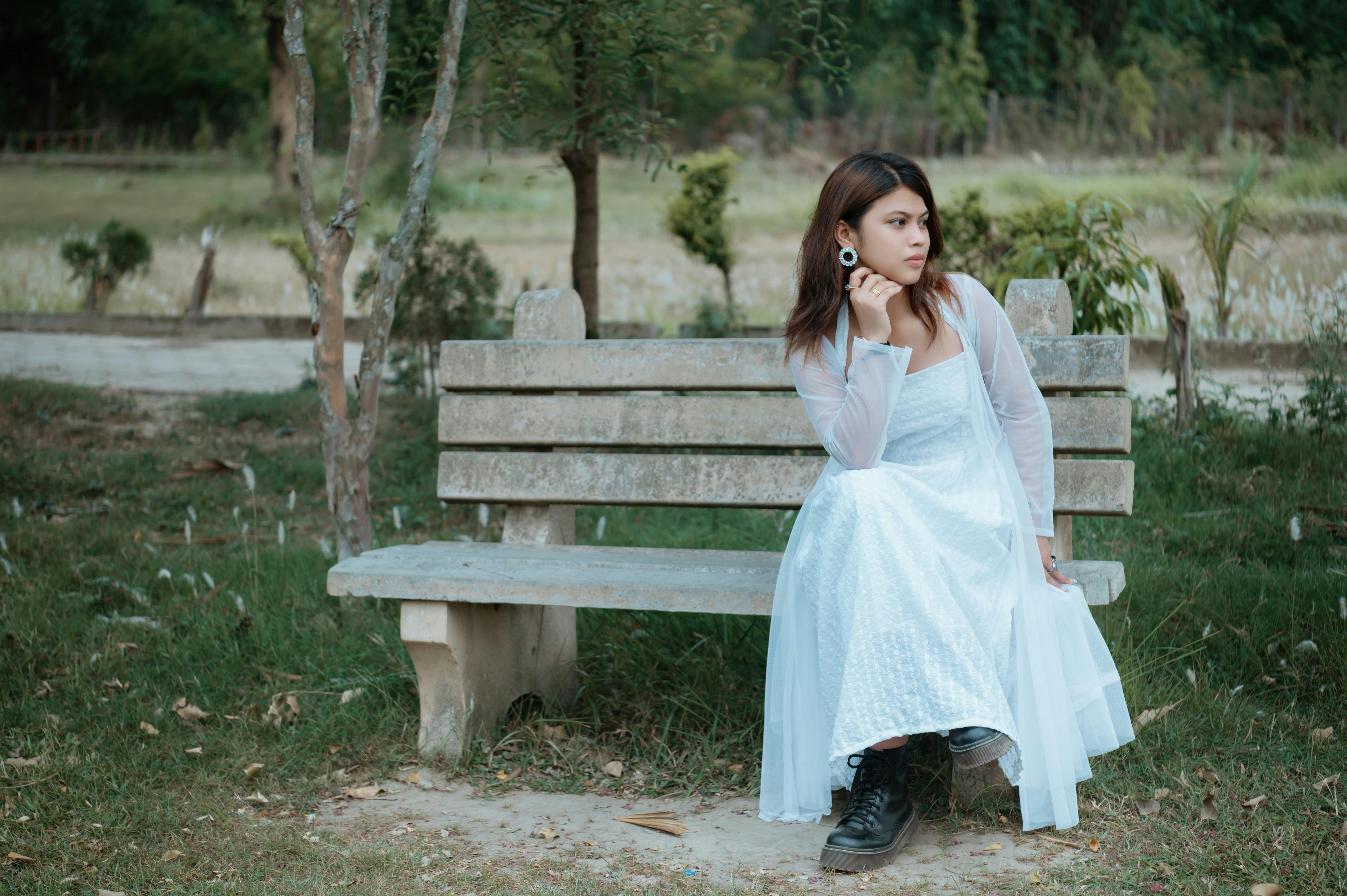Young Woman in Dress Sitting on Bench in Forest · Free Stock Photo