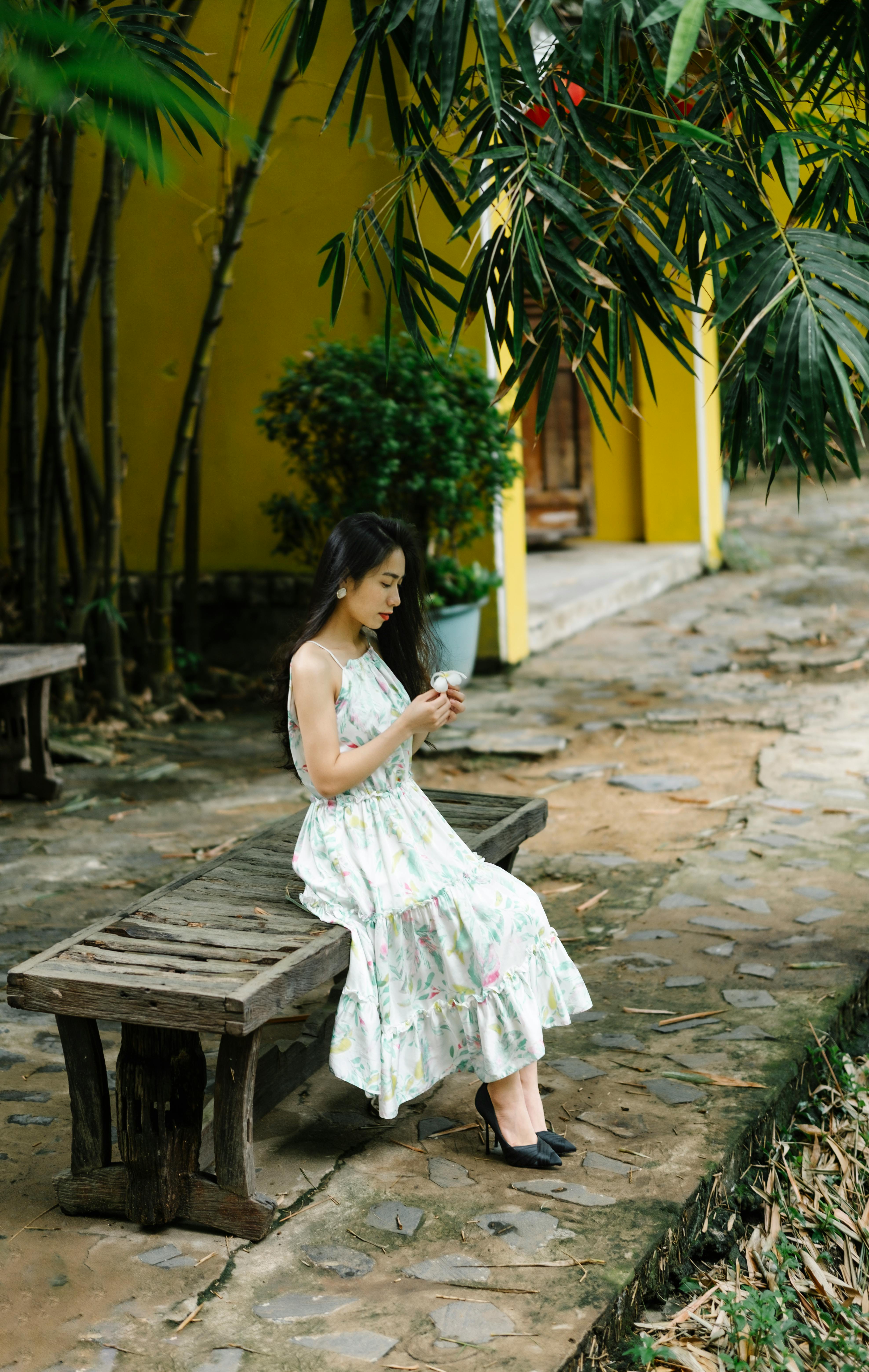 Woman in Flora Dress Sitting on Wooden Bench · Free Stock Photo