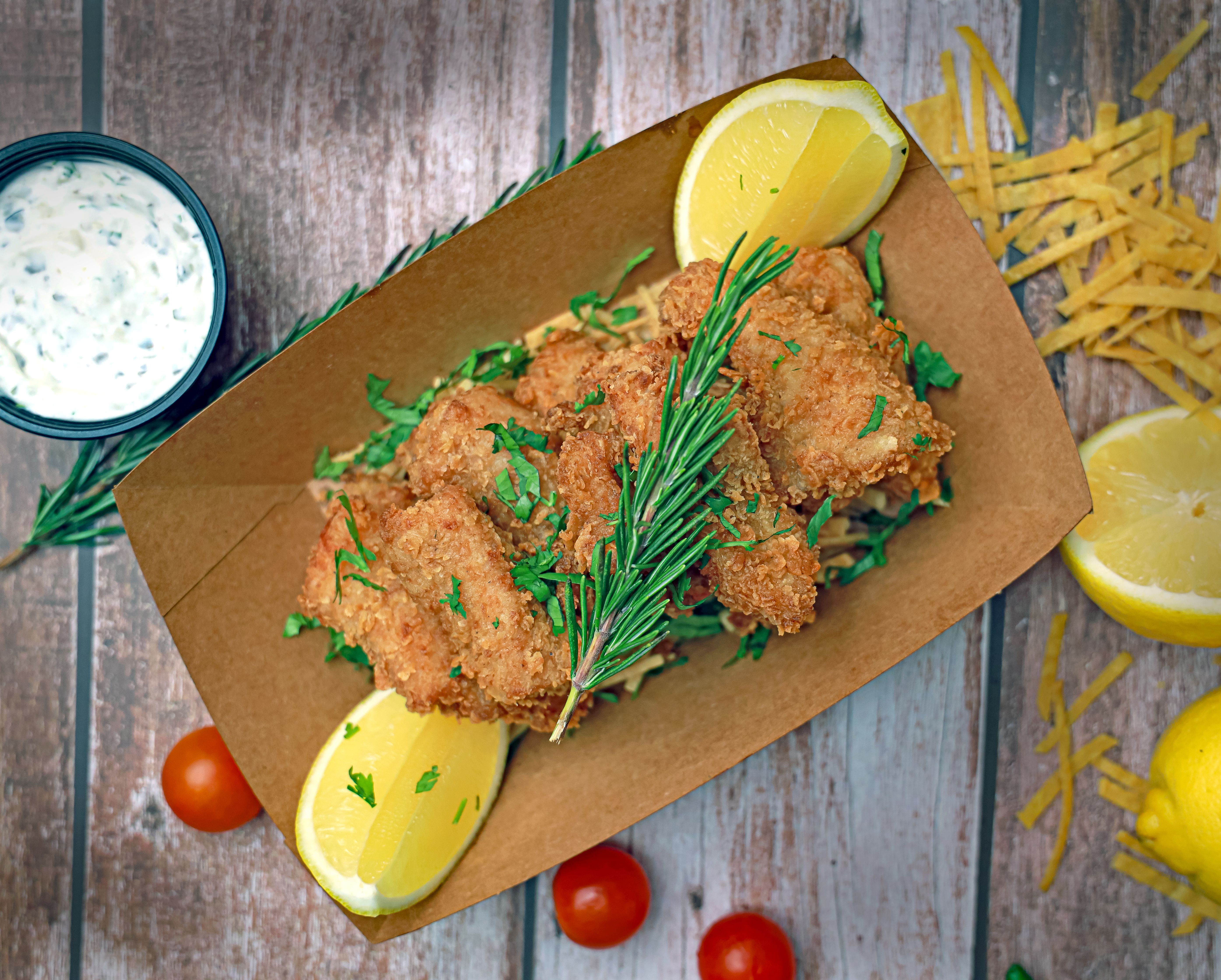 A tray with fried fish, lemon wedges and tomatoes · Free Stock Photo