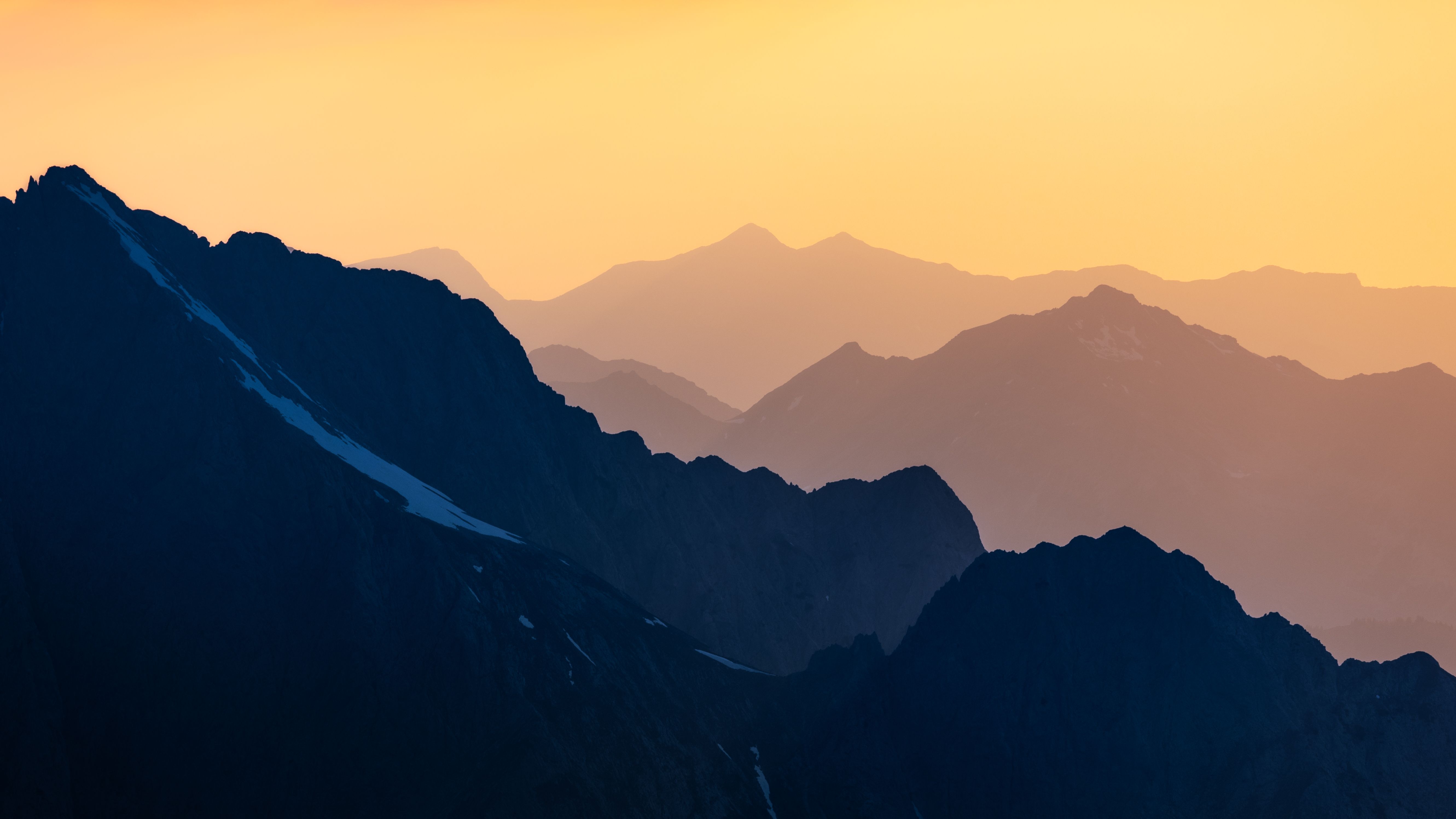 A sunset over mountains with a mountain range in the background · Free ...