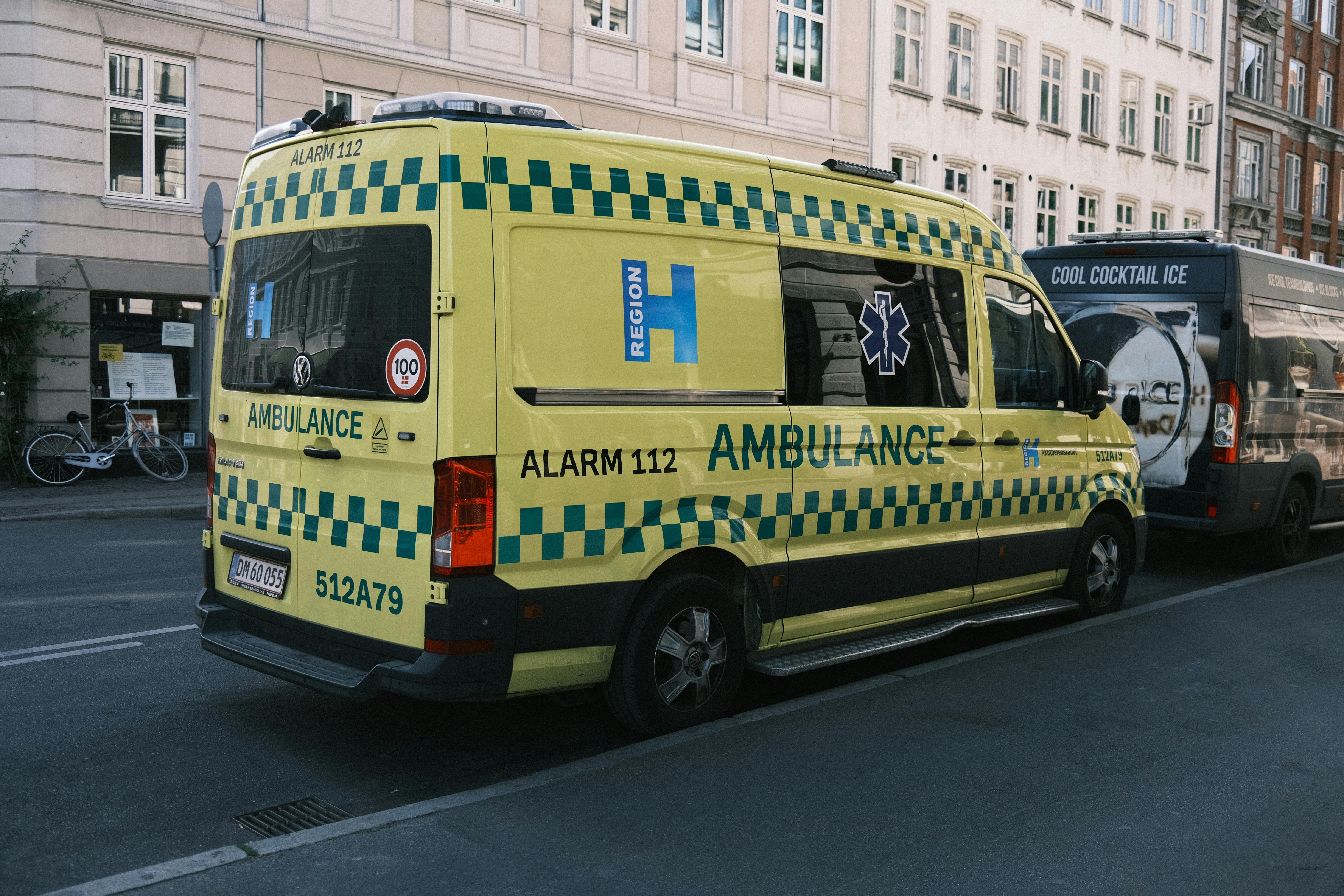 An ambulance is parked on the street next to a building · Free Stock Photo