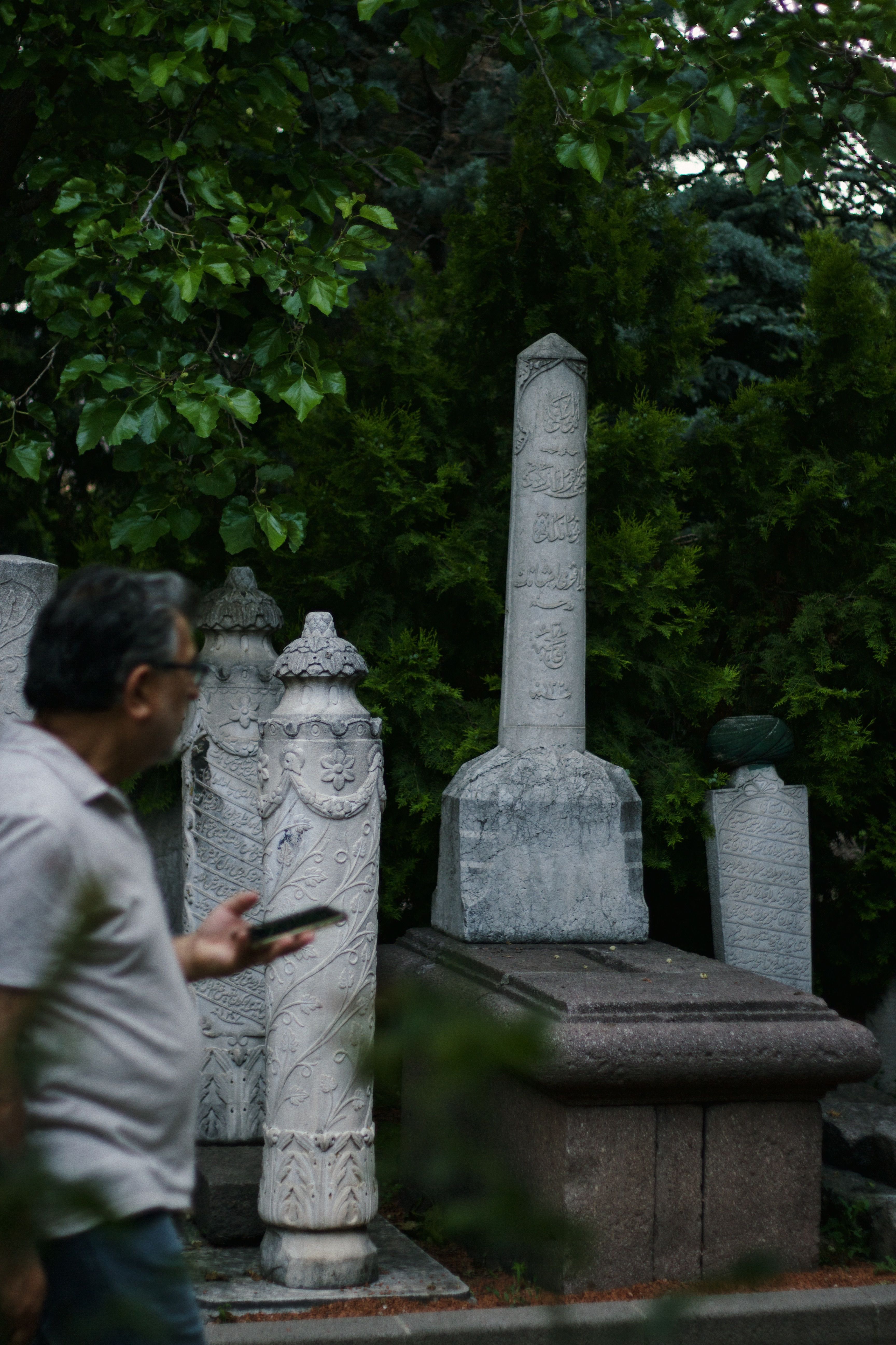 Man Walking near Tombstones on Cemetery · Free Stock Photo
