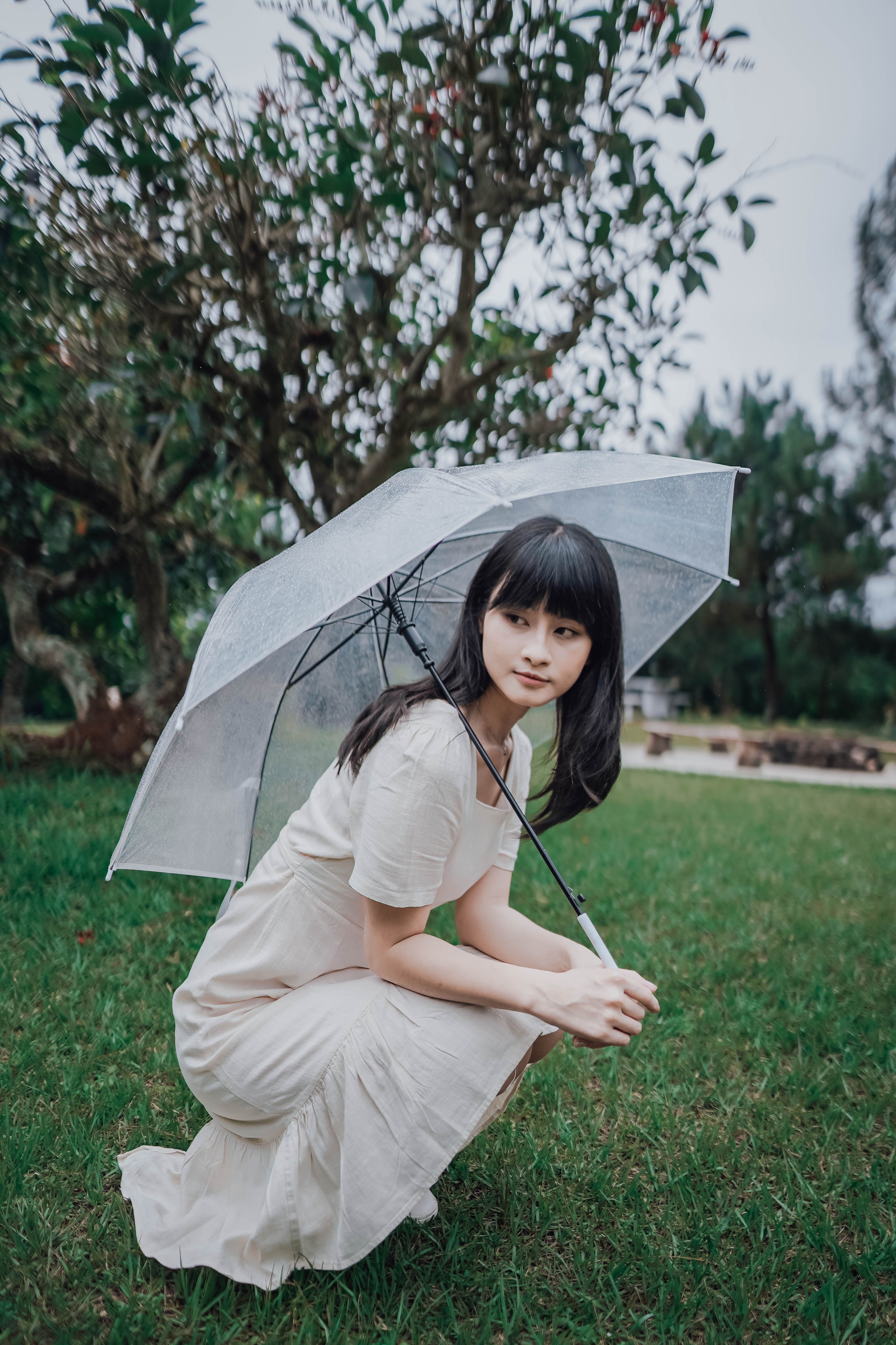 Woman Crouching under Transparent Umbrella · Free Stock Photo