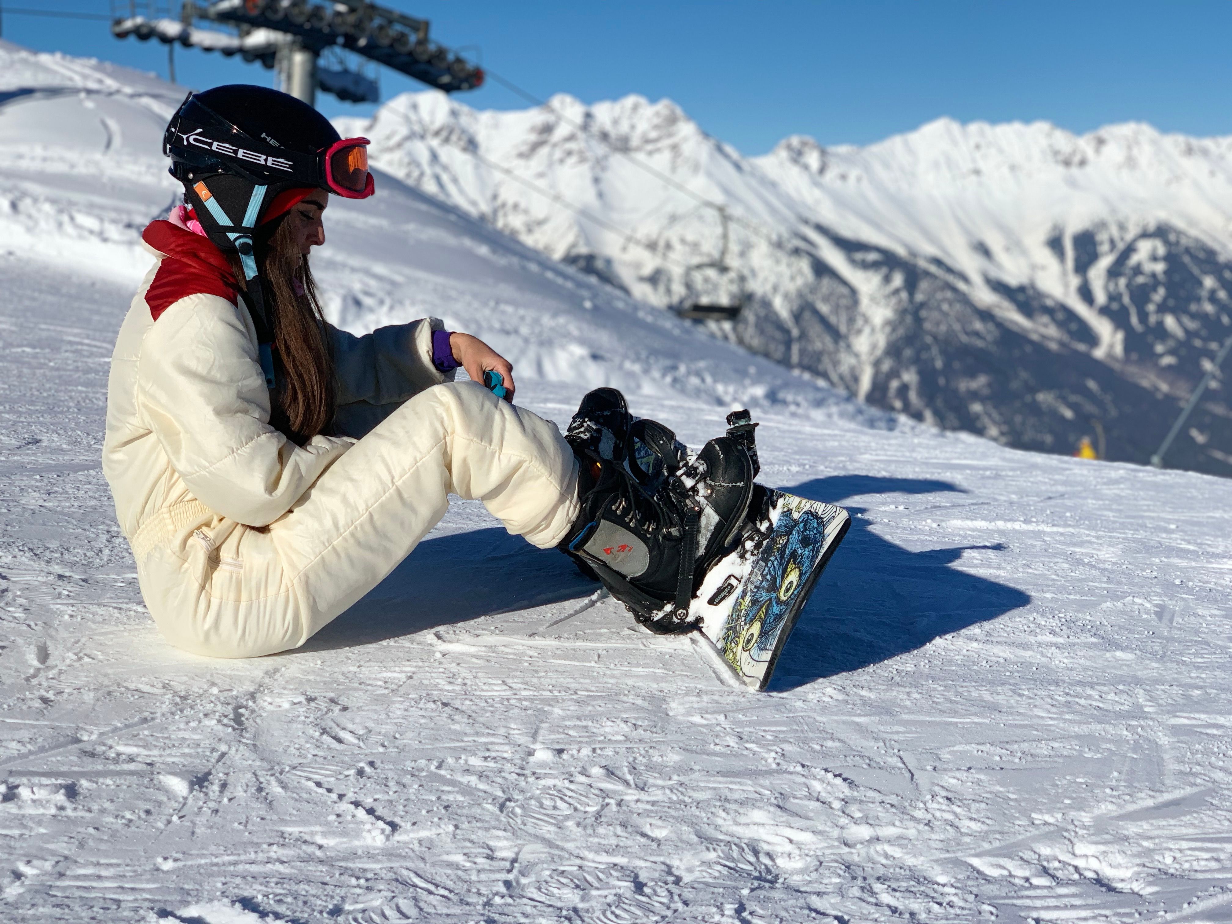 Young Woman with a Snowboard Sitting on the Slope · Free Stock Photo