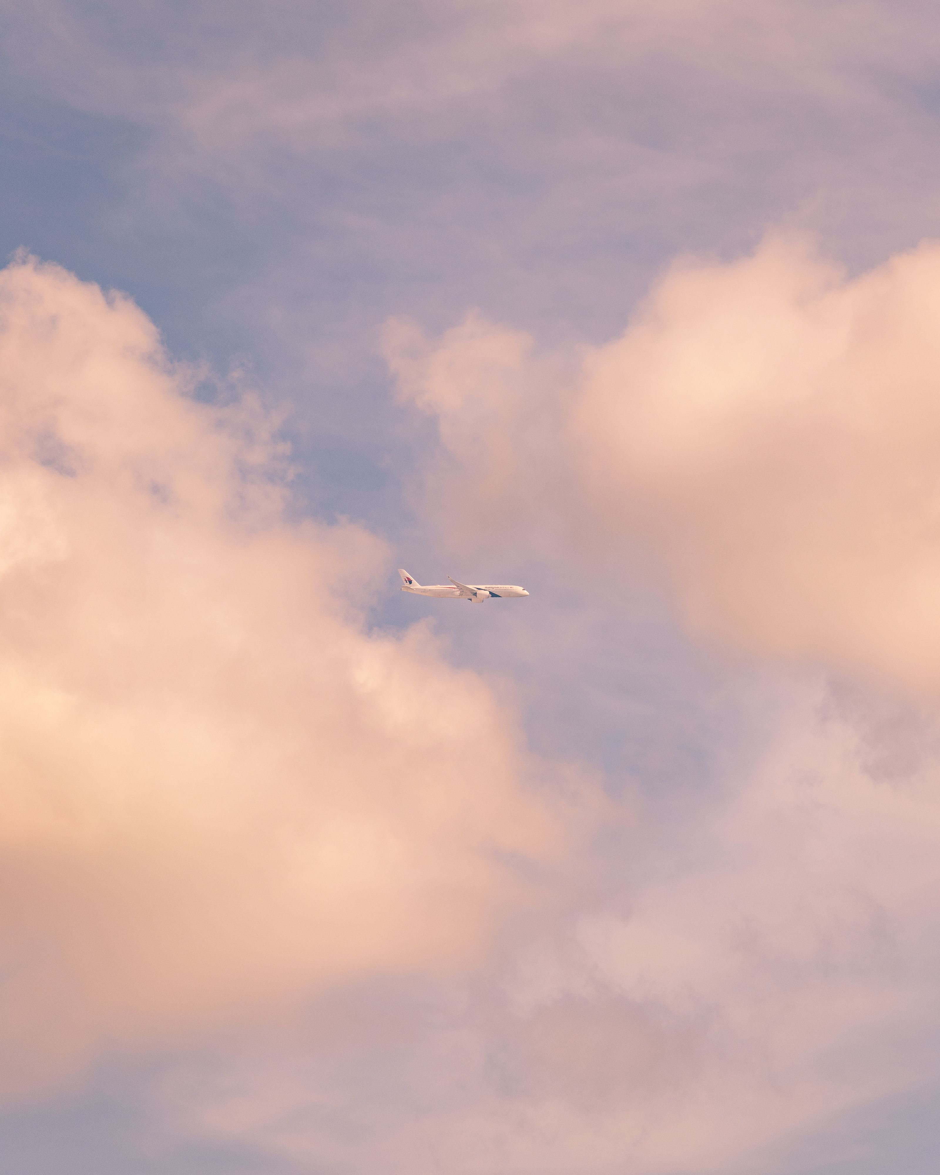 A plane flying through the sky with some clouds · Free Stock Photo
