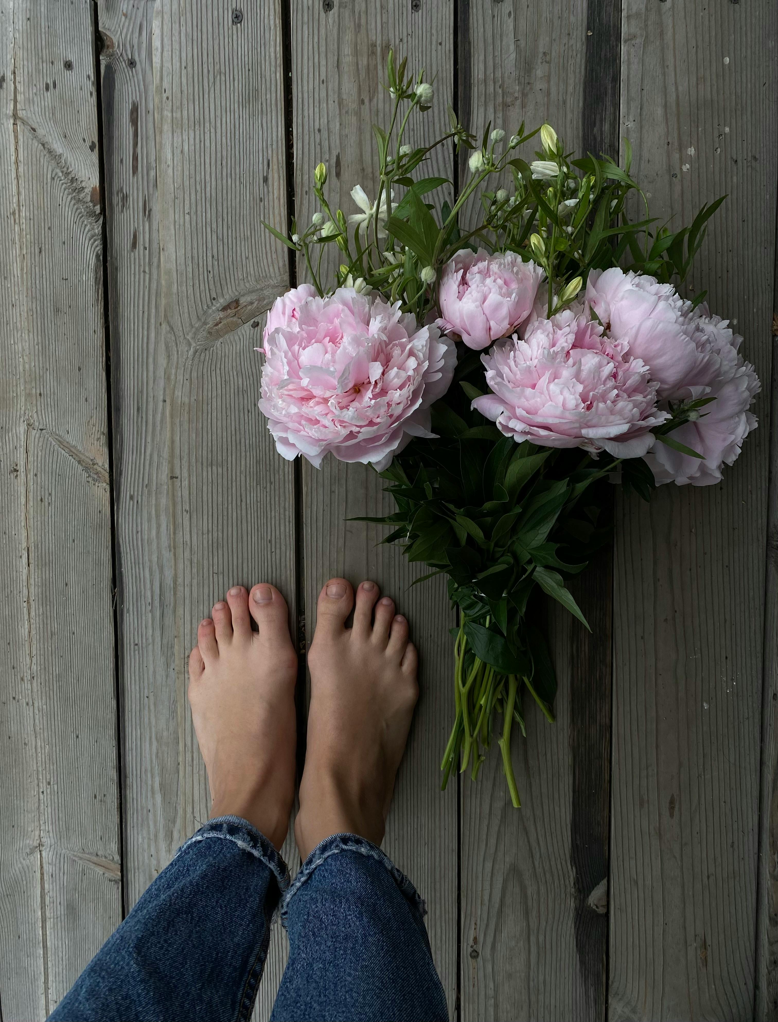 Womens Feet and a Bouquet of Flowers on Wooden Floor · Free Stock Photo
