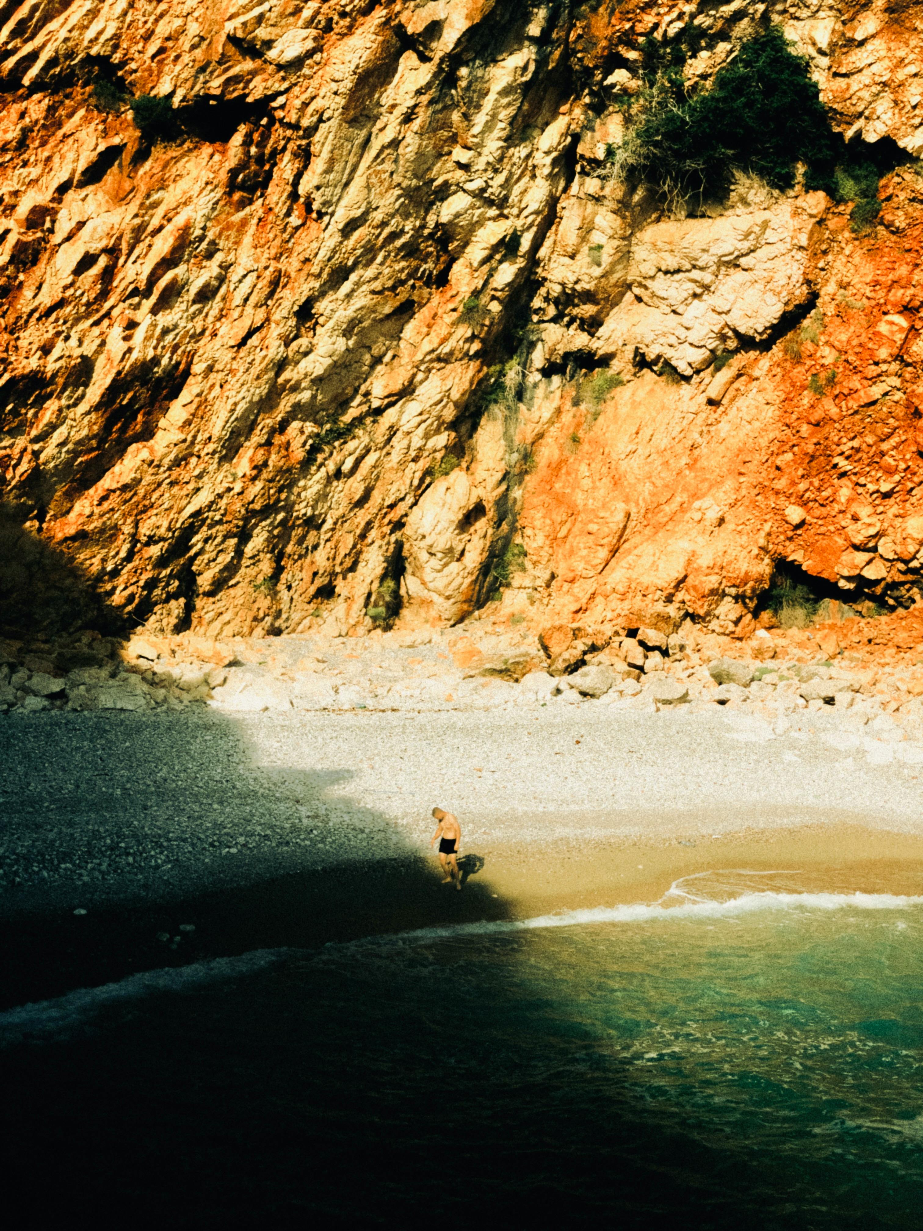 Man on Beach under Rocks · Free Stock Photo