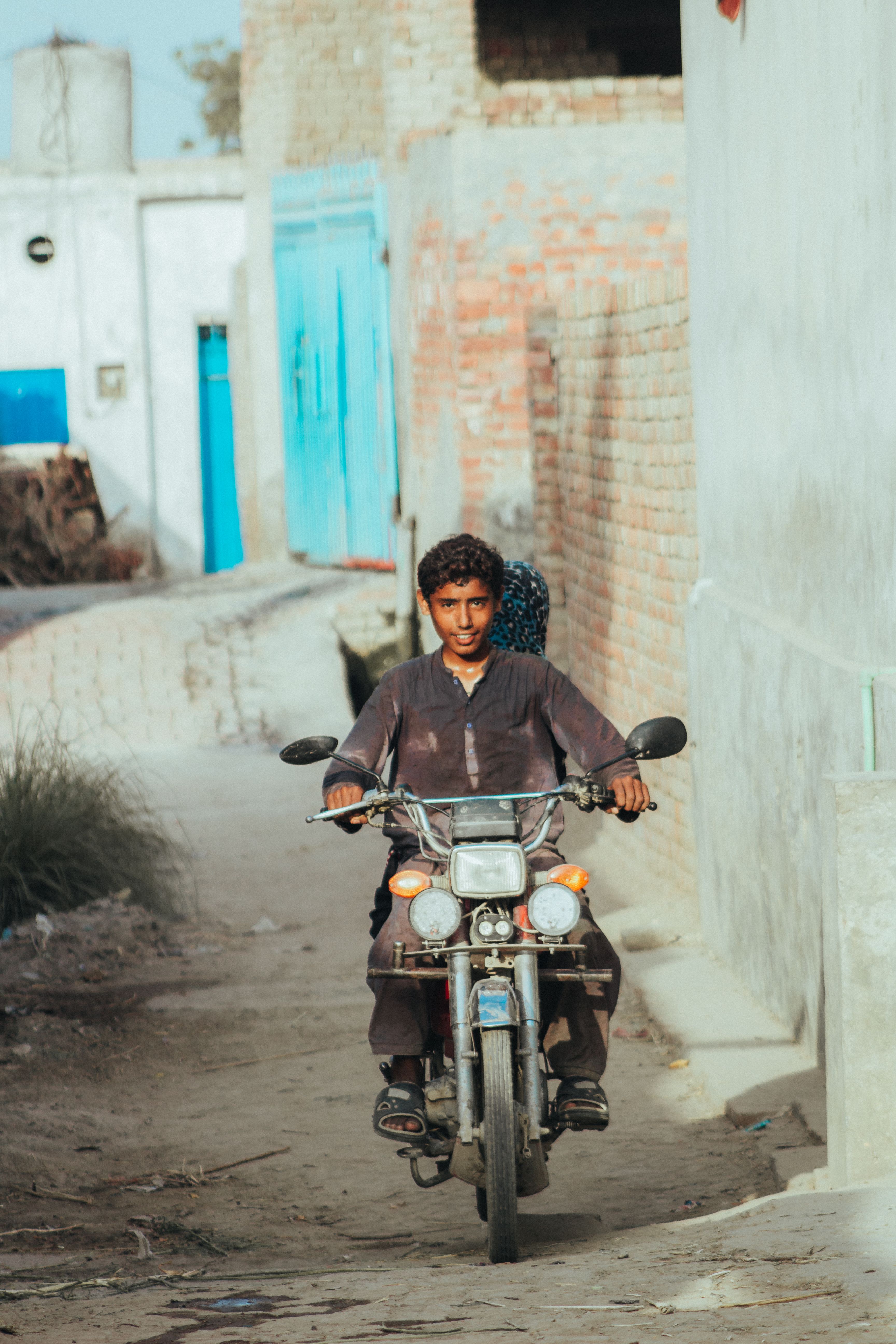 Teenager Riding a Motorcycle Along the Buildings · Free Stock Photo