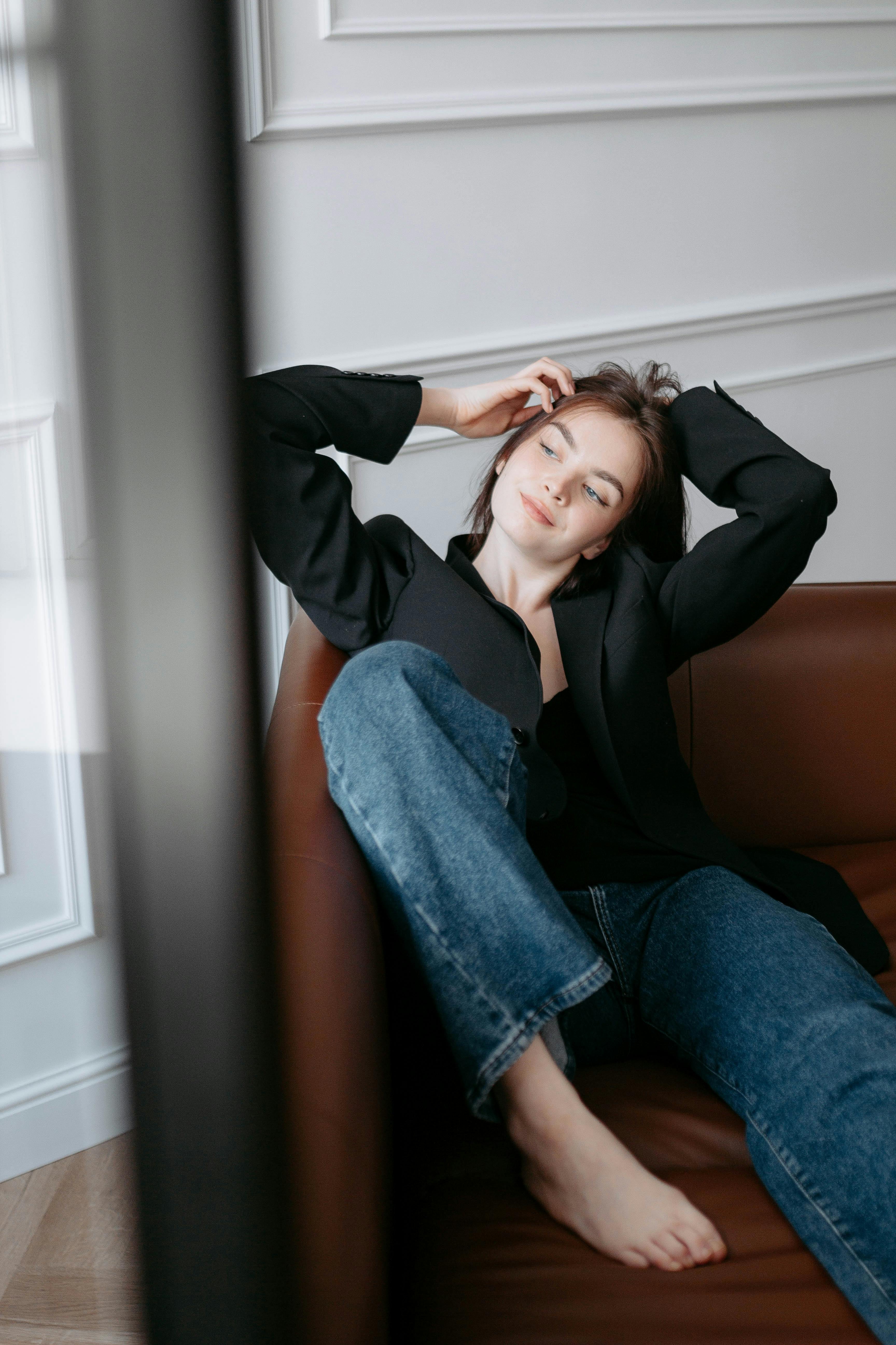 Pretty Young Woman in Black Jacket and Jeans Sitting on Sofa · Free ...