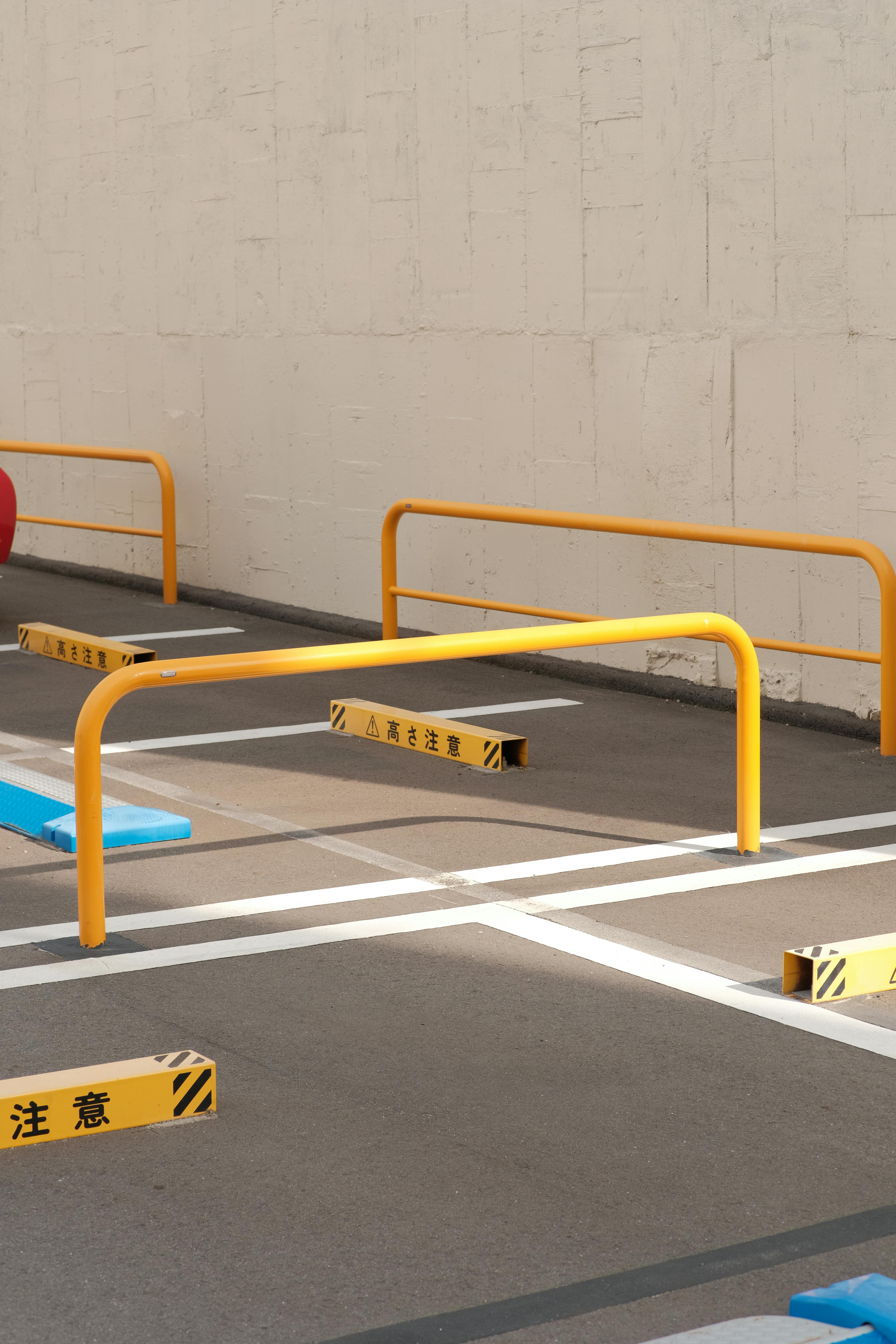 Yellow Safety Barriers by Wall in Parking Lot · Free Stock Photo