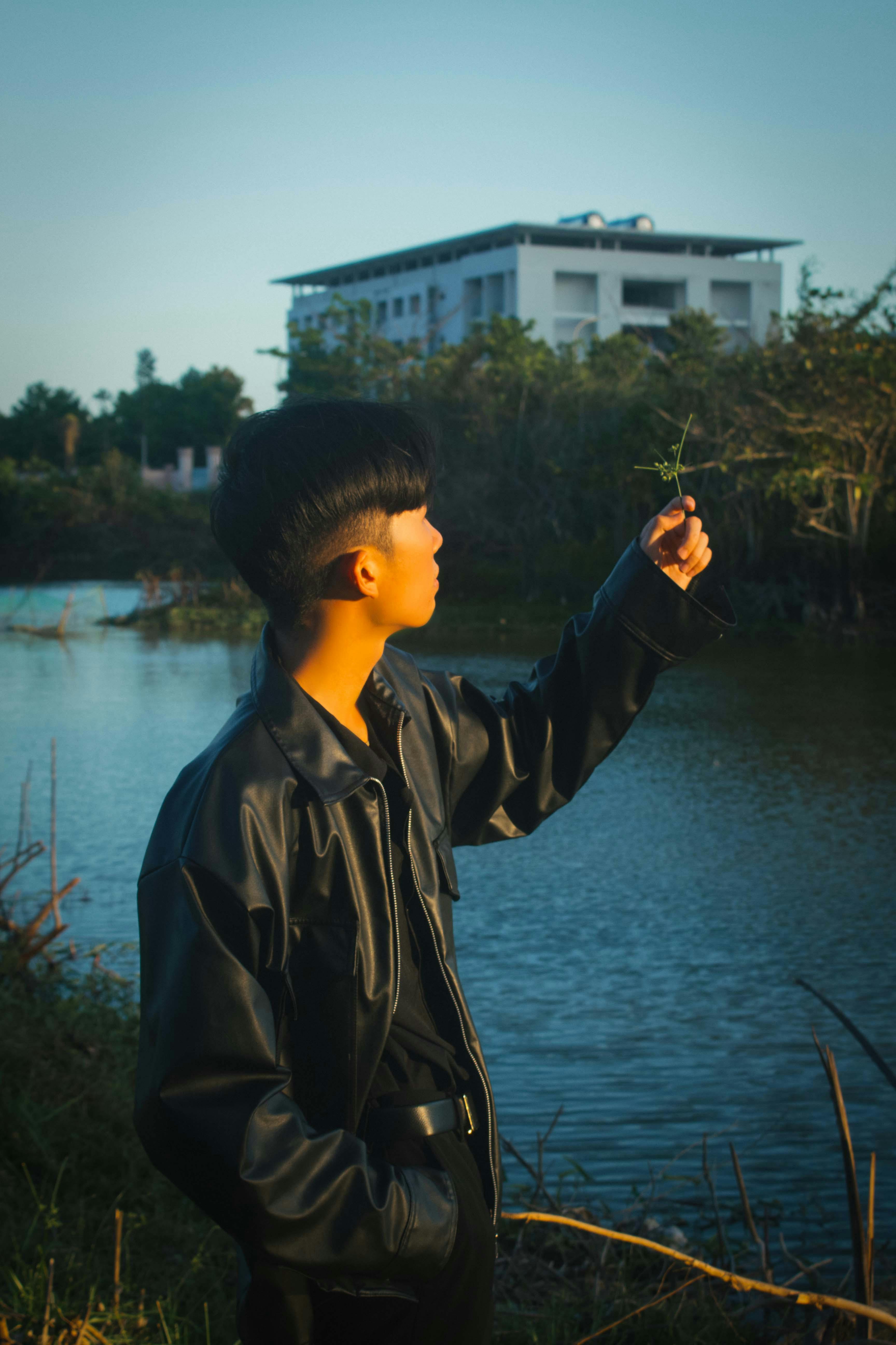 Young Man Standing by the River and Catching a Dragonfly · Free Stock Photo