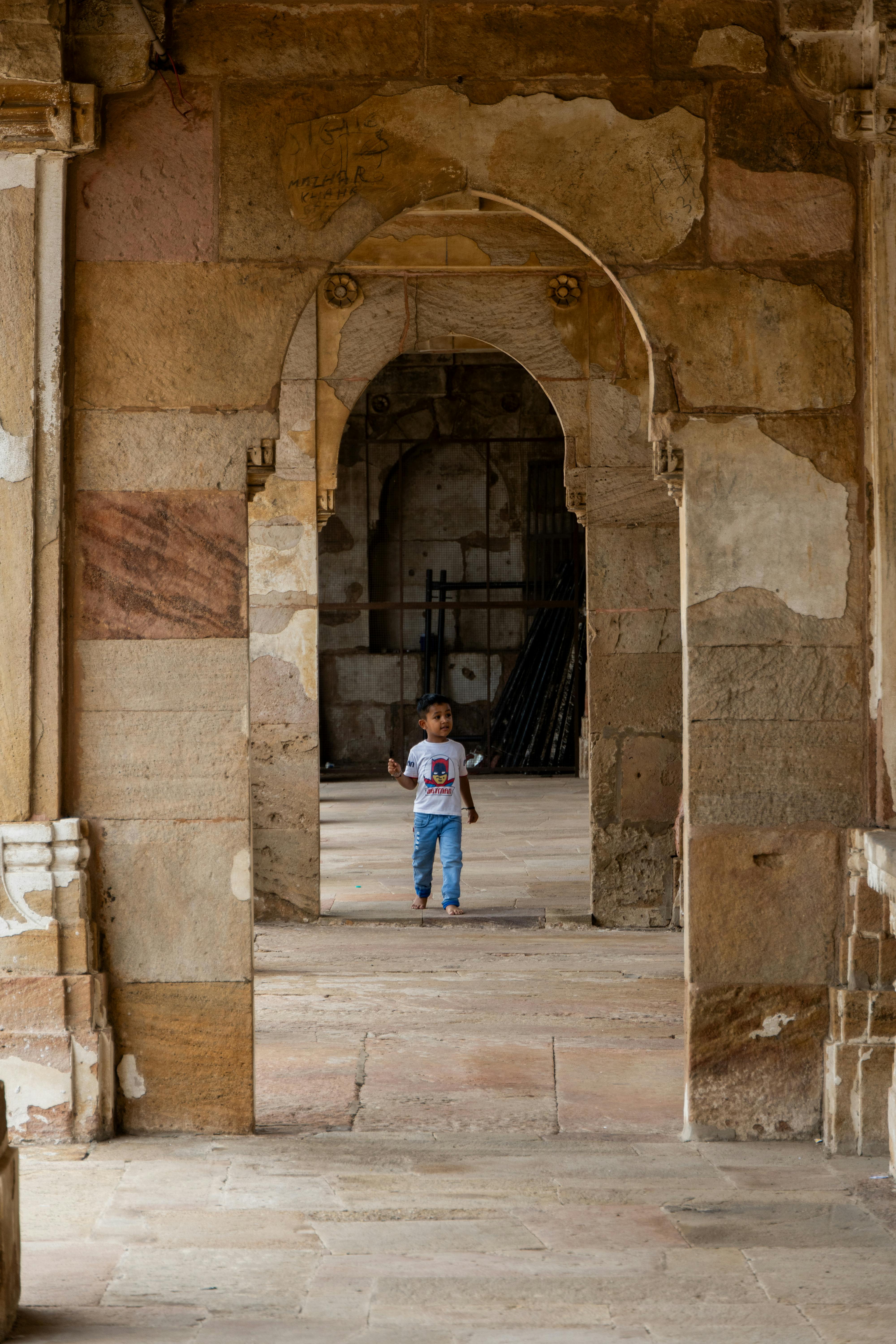 Boy Walking on Arcade Walkway · Free Stock Photo