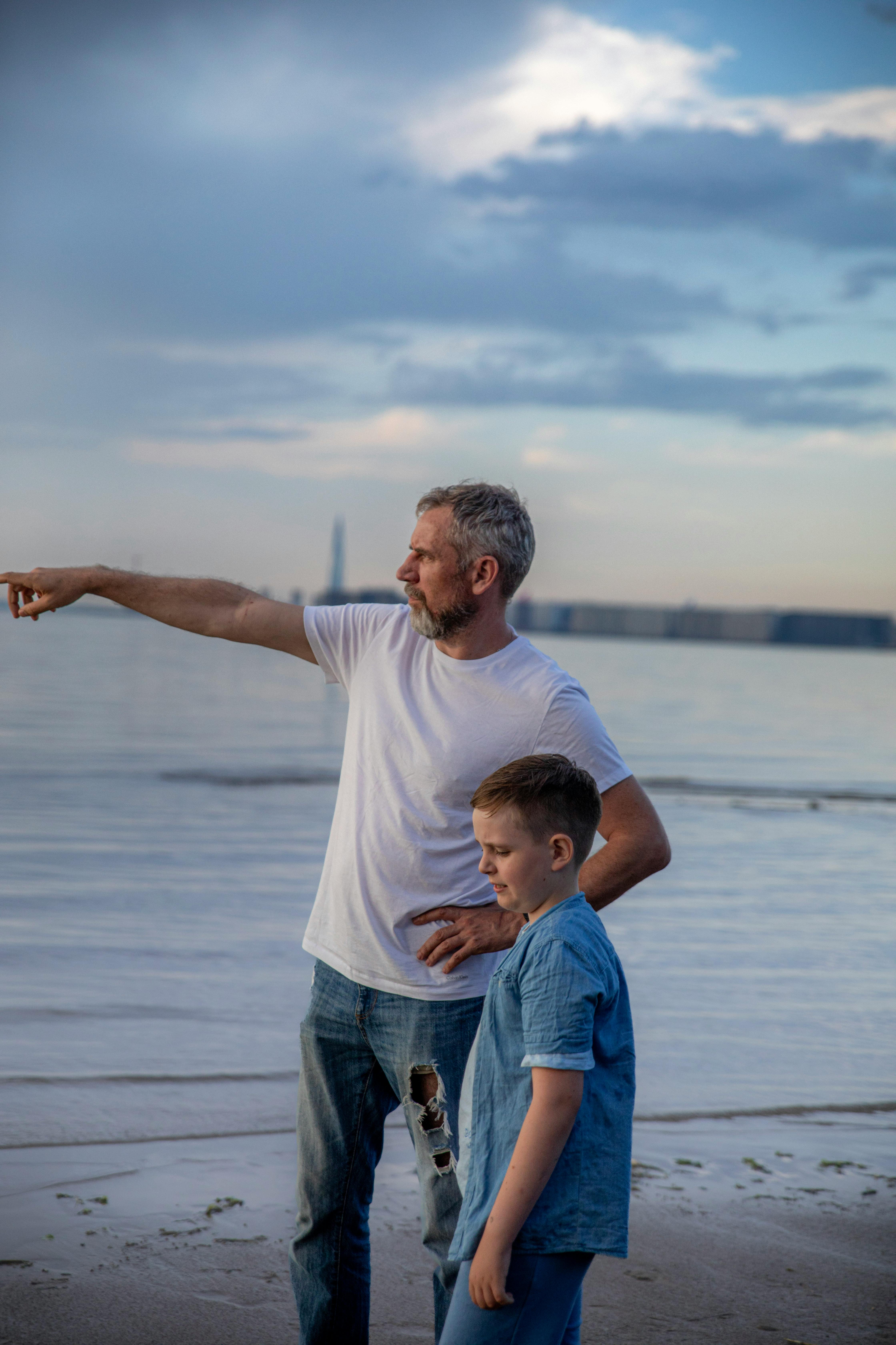 A man and a boy pointing at something on the beach · Free Stock Photo