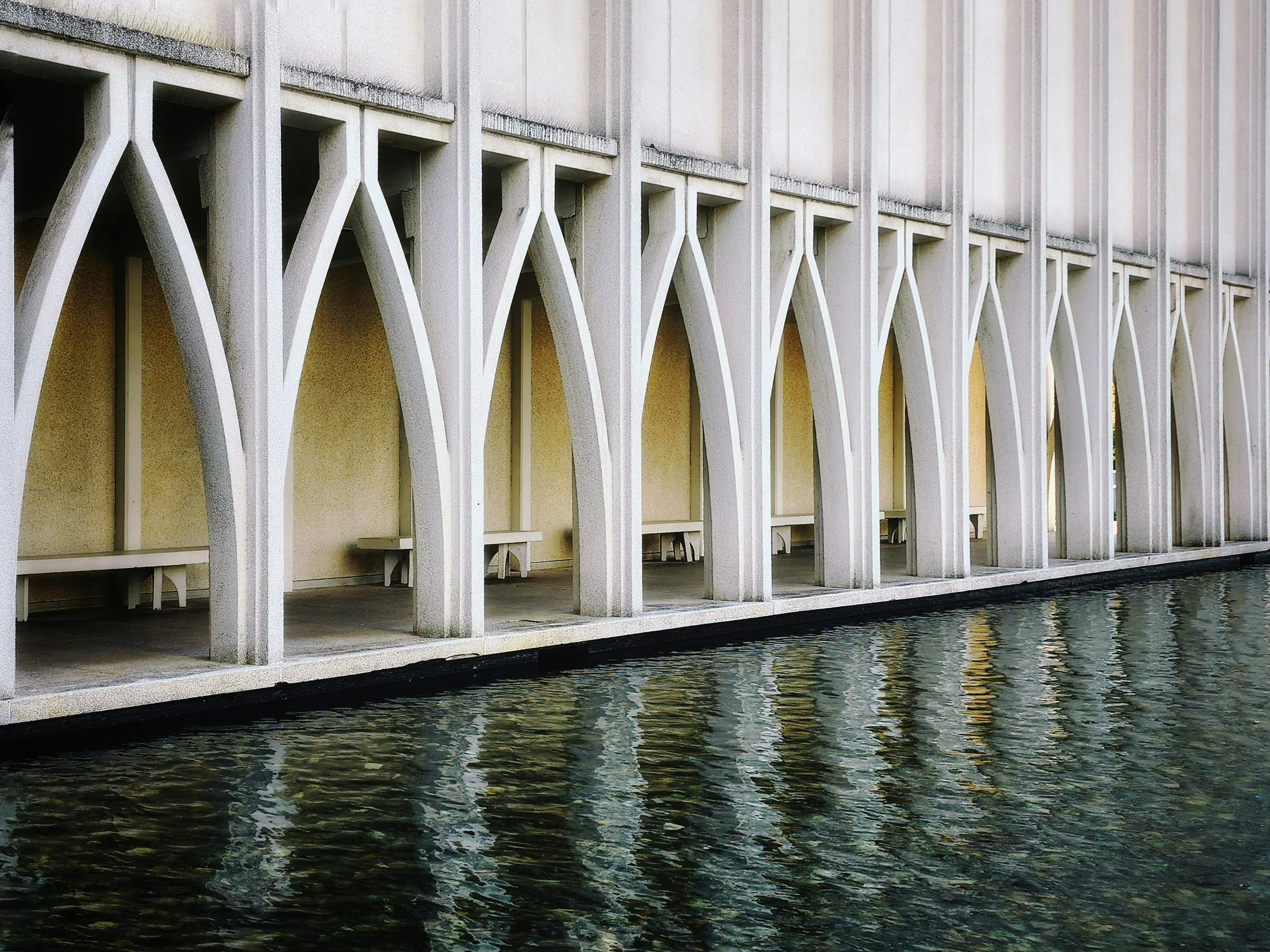 A building with white columns and a water reflection · Free Stock Photo