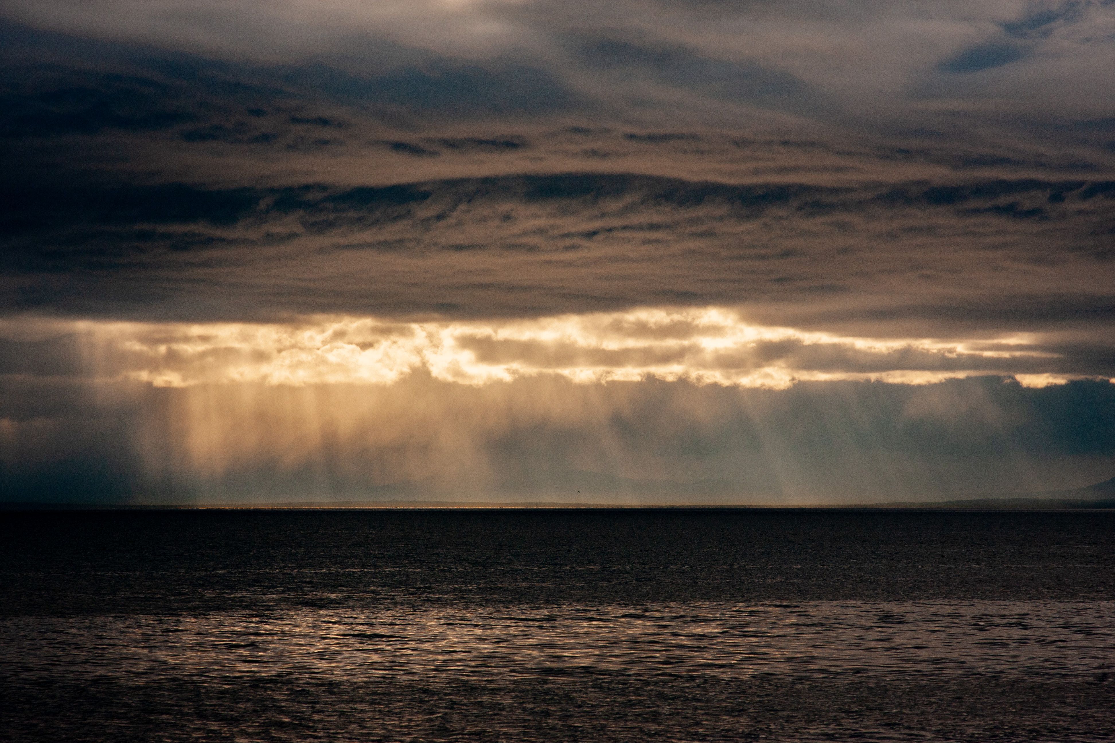 Sunbeams behind Rain Clouds over Sea · Free Stock Photo