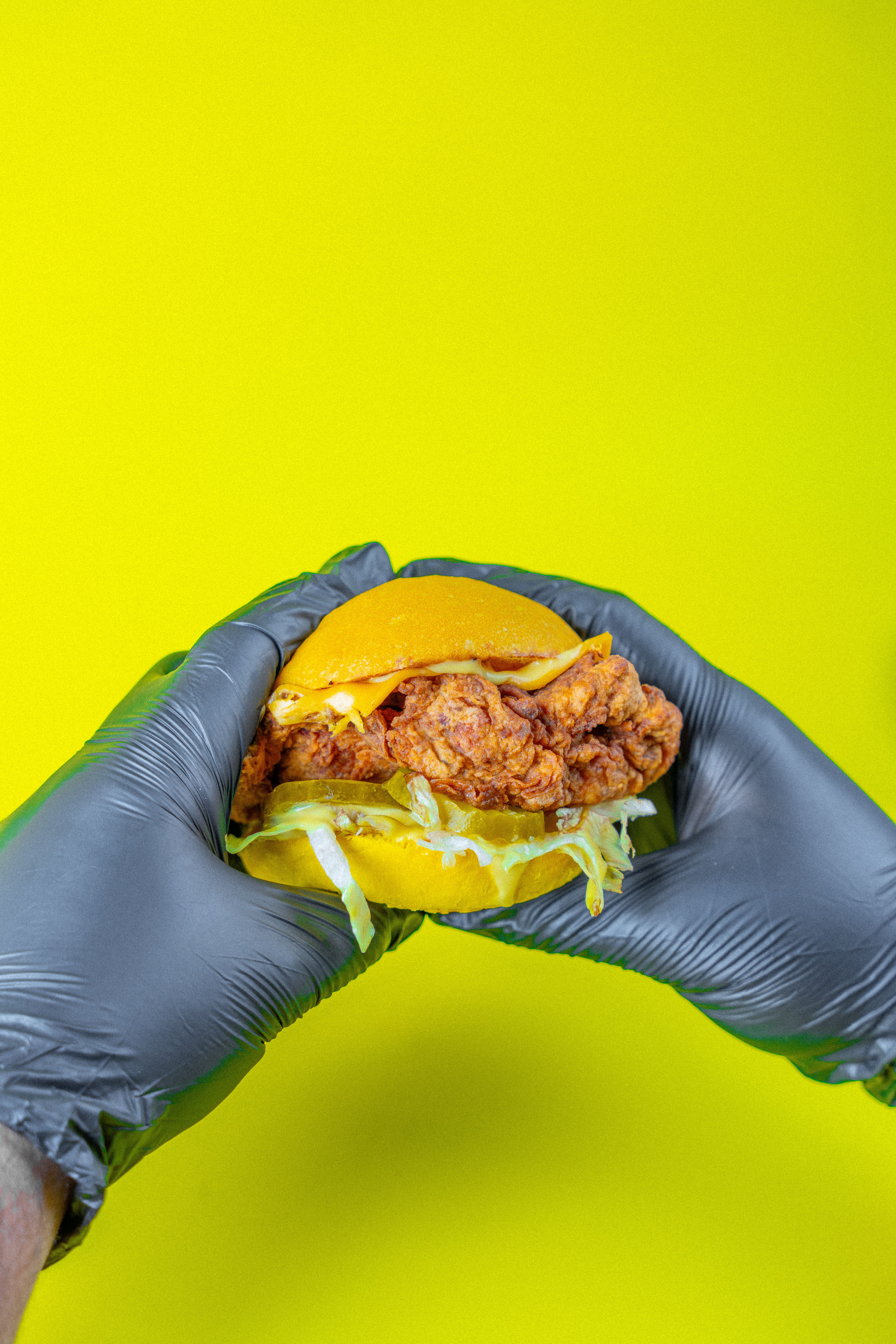 Hands in Gloves Squeezing a Burger · Free Stock Photo