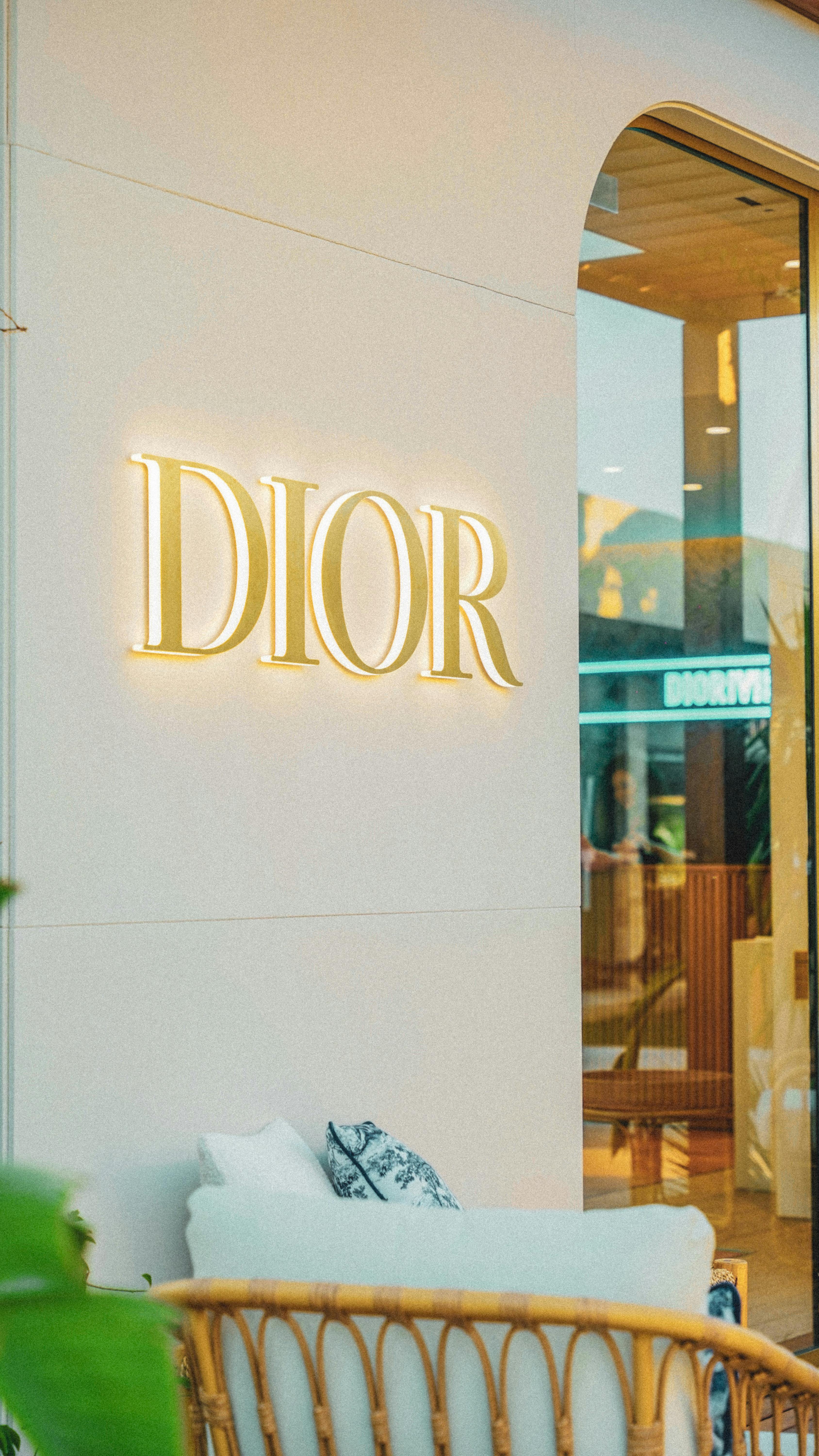 Glowing Dior Sign Hanging on a White Wall · Free Stock Photo
