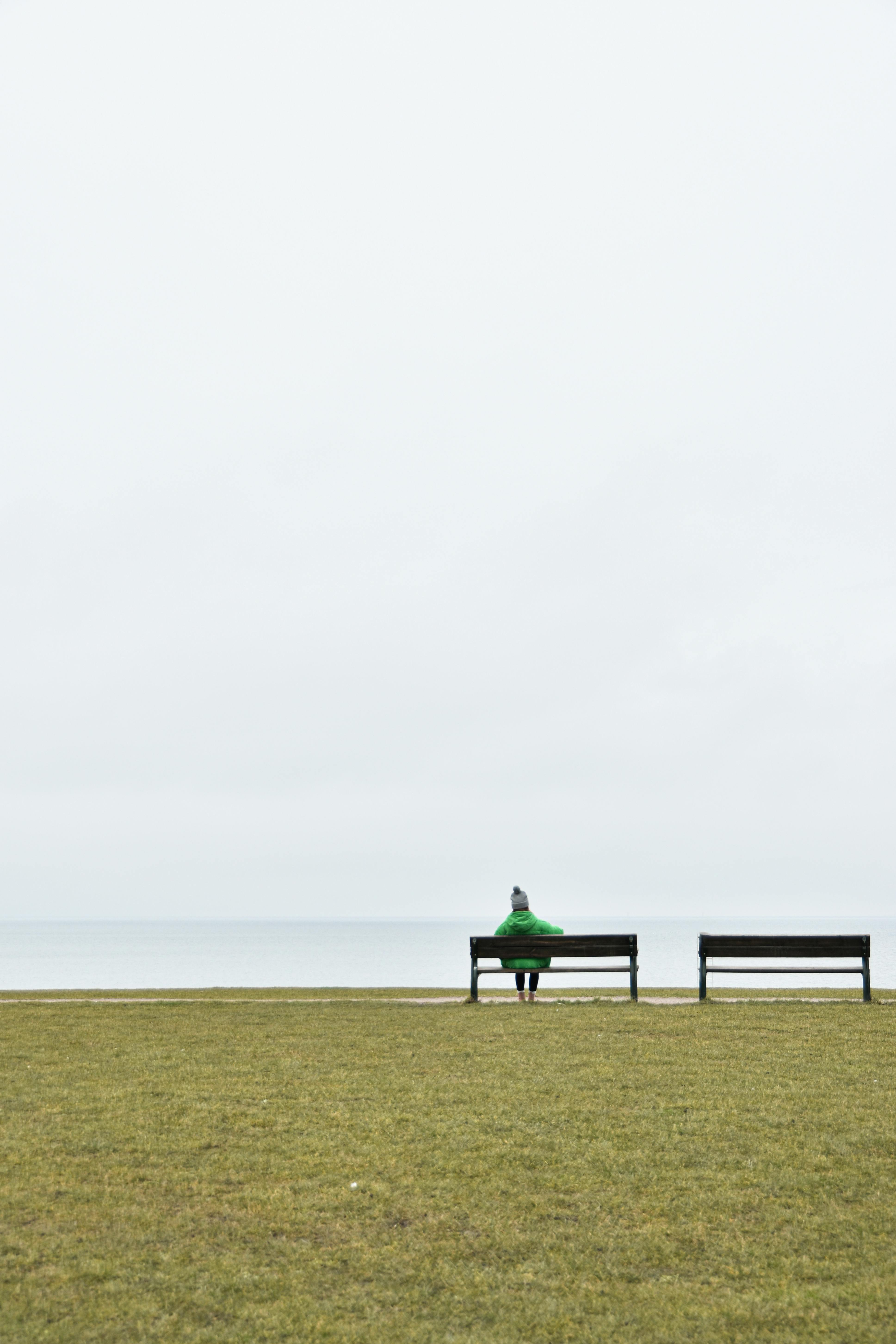 A Person Sitting alone on a Bench on the Seashore · Free Stock Photo