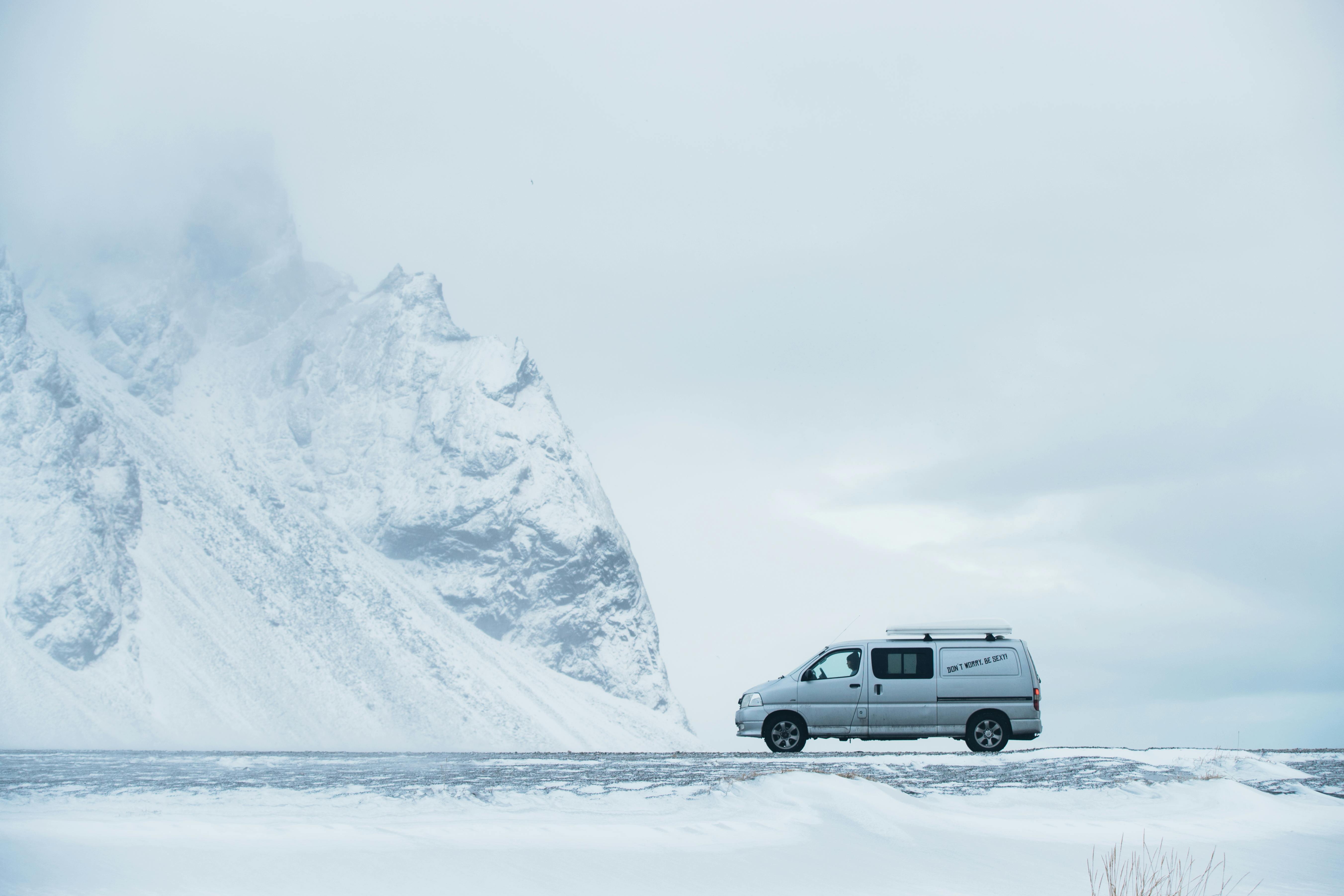 A van is parked in the snow near a mountain · Free Stock Photo