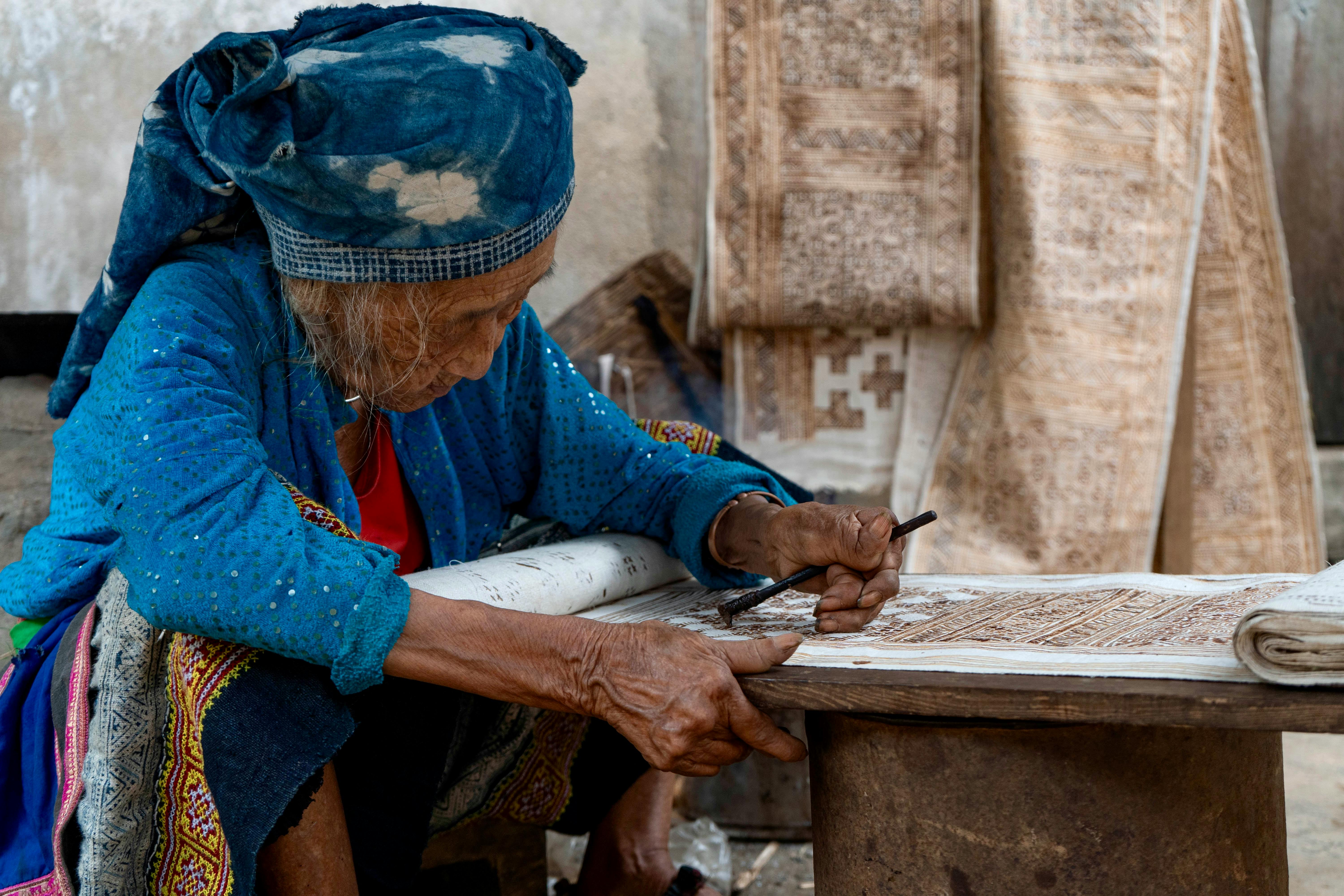 Elderly Woman Decorating Fabric with Traditional Pattern · Free Stock Photo