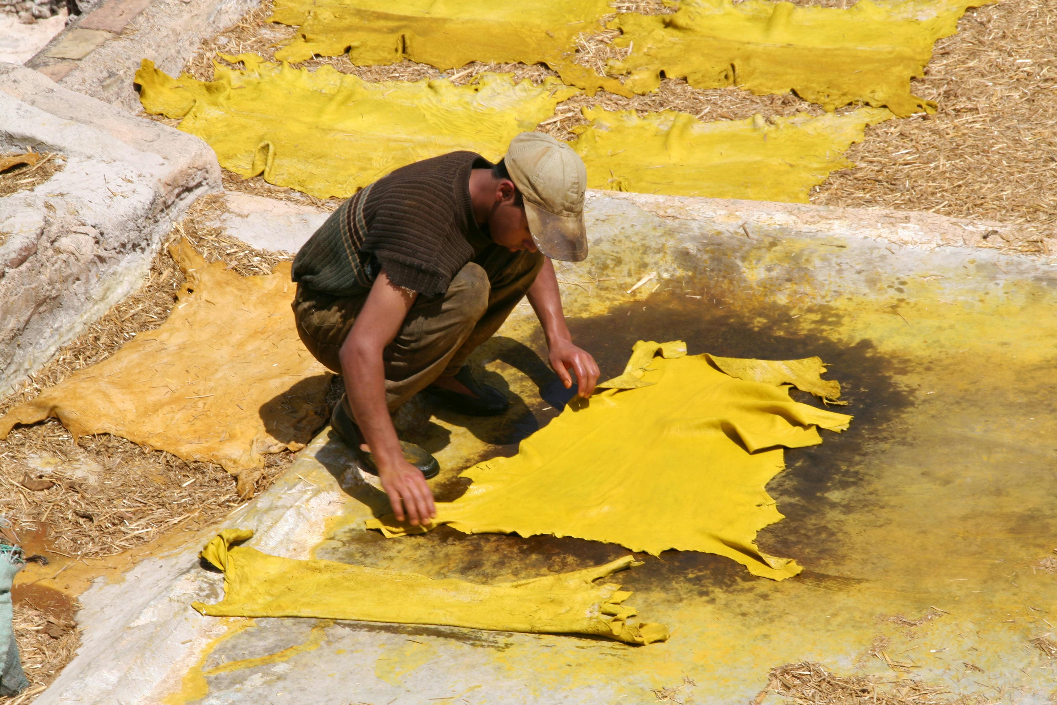 Worker Crouching with Yellow Fabric · Free Stock Photo