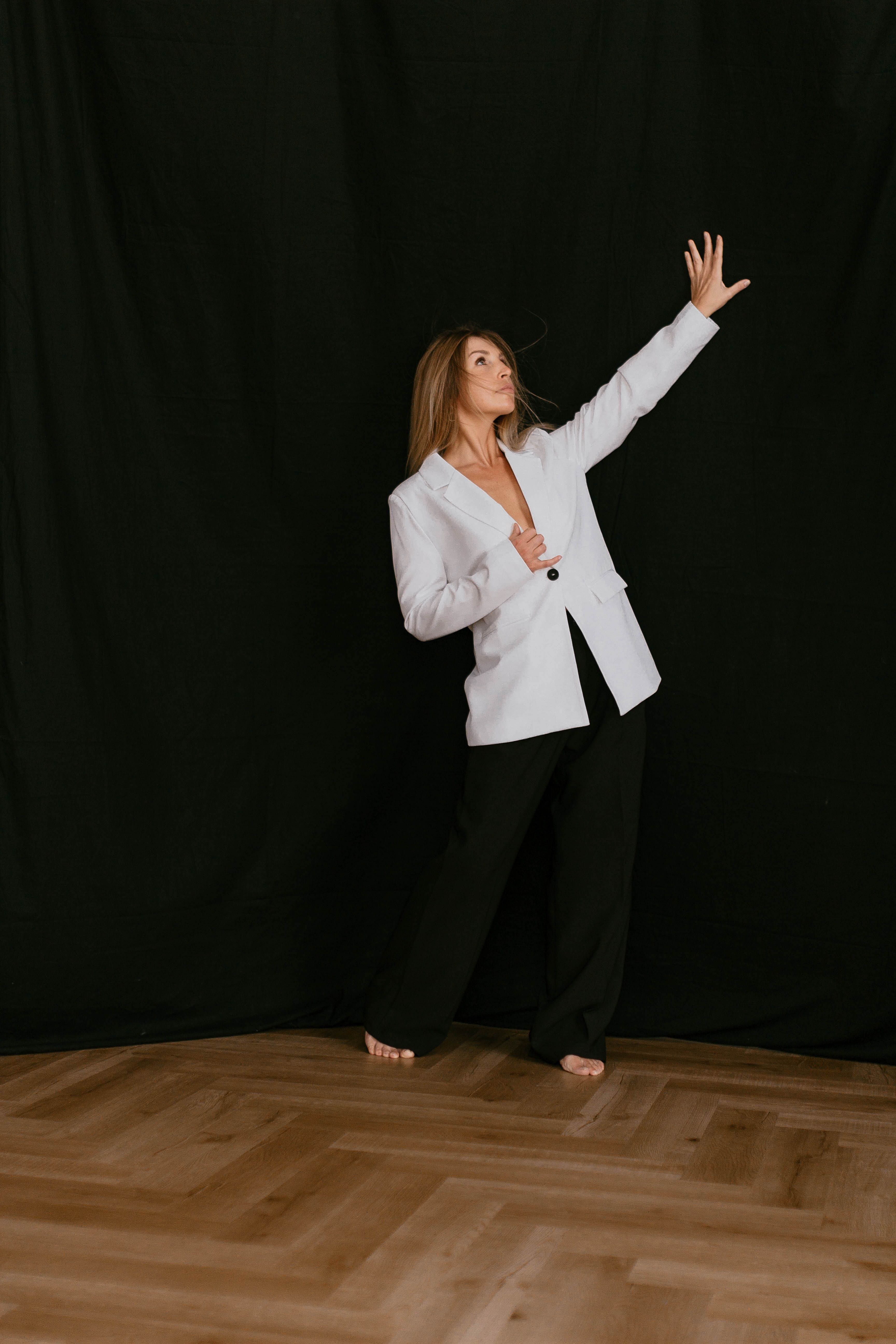 Woman in White Jacket Standing with Arm Raised · Free Stock Photo