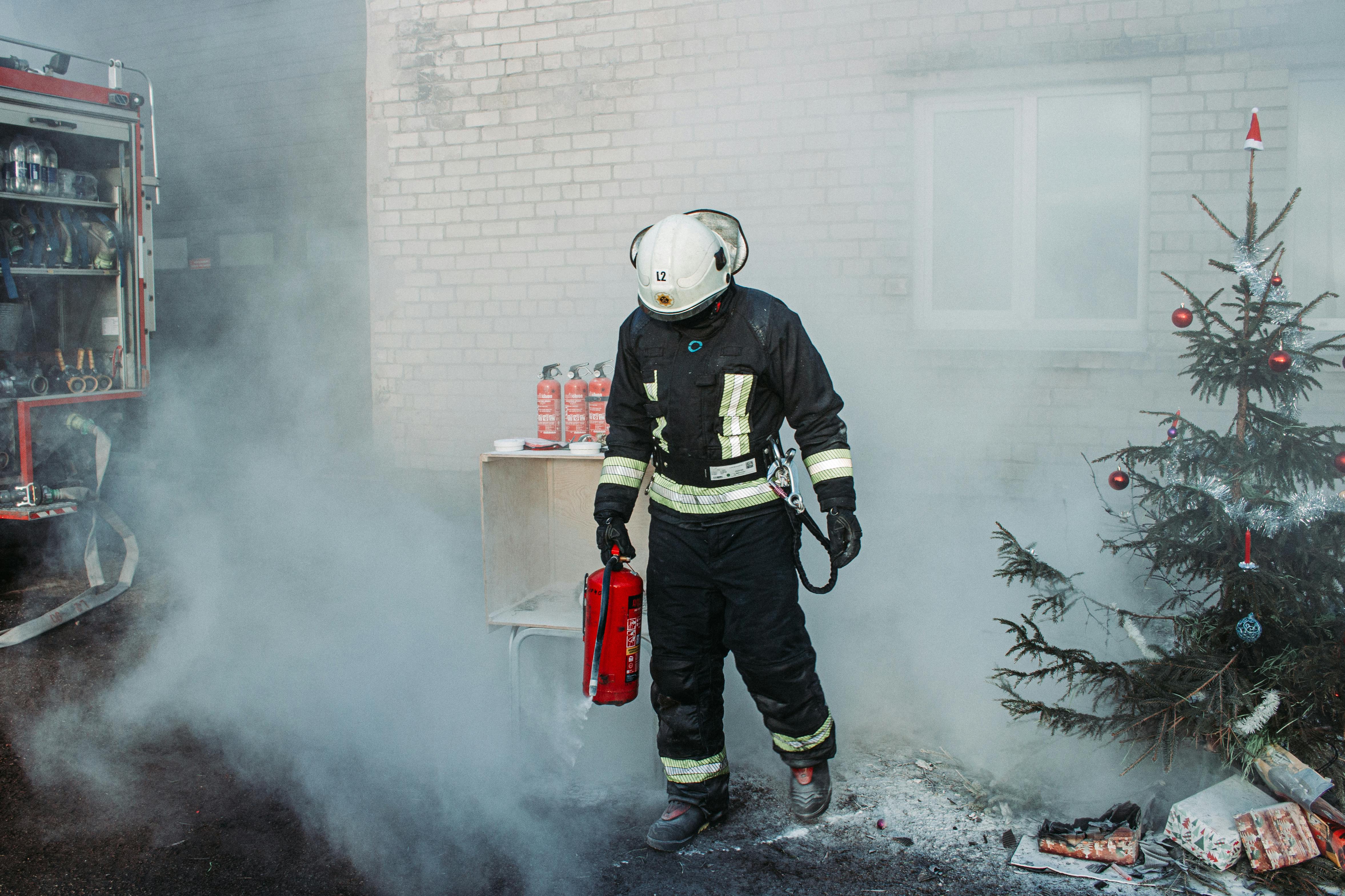 Firefighter with Extinguisher near Christmas Tree · Free Stock Photo