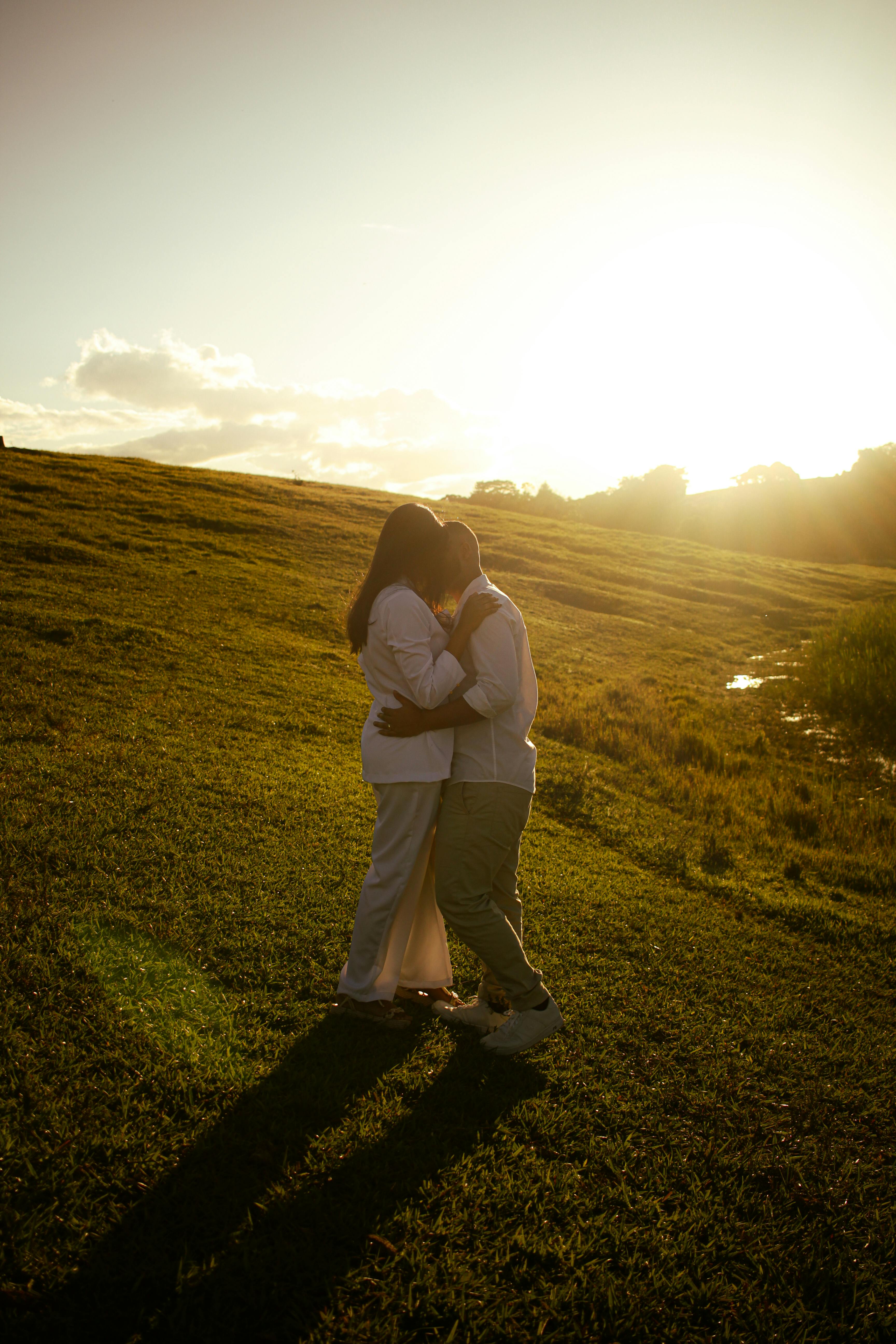 Sunset Sunlight over Hugging Couple on Grassland · Free Stock Photo