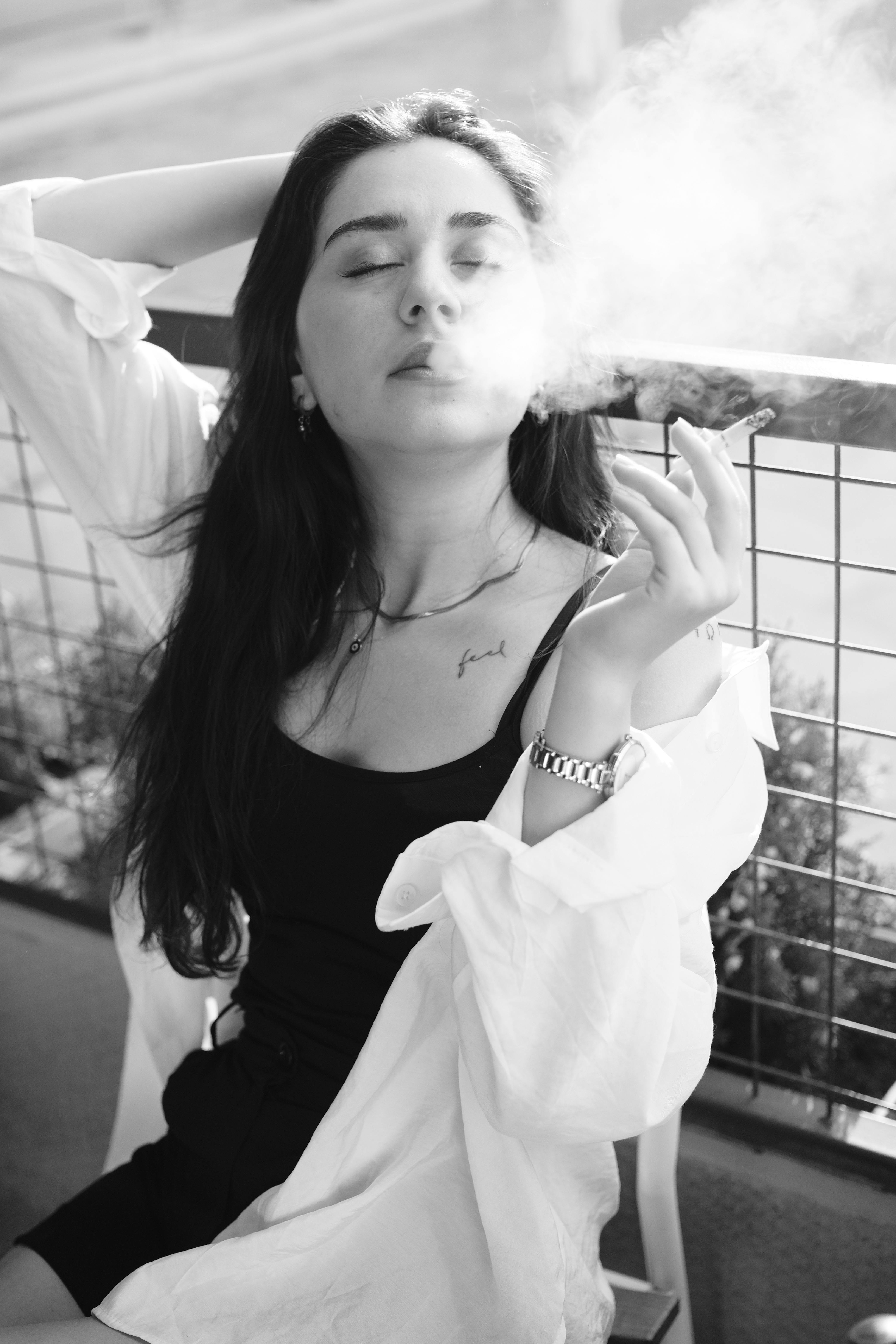 Woman Smoking Cigarette and Sitting by Fishnet Railing · Free Stock Photo