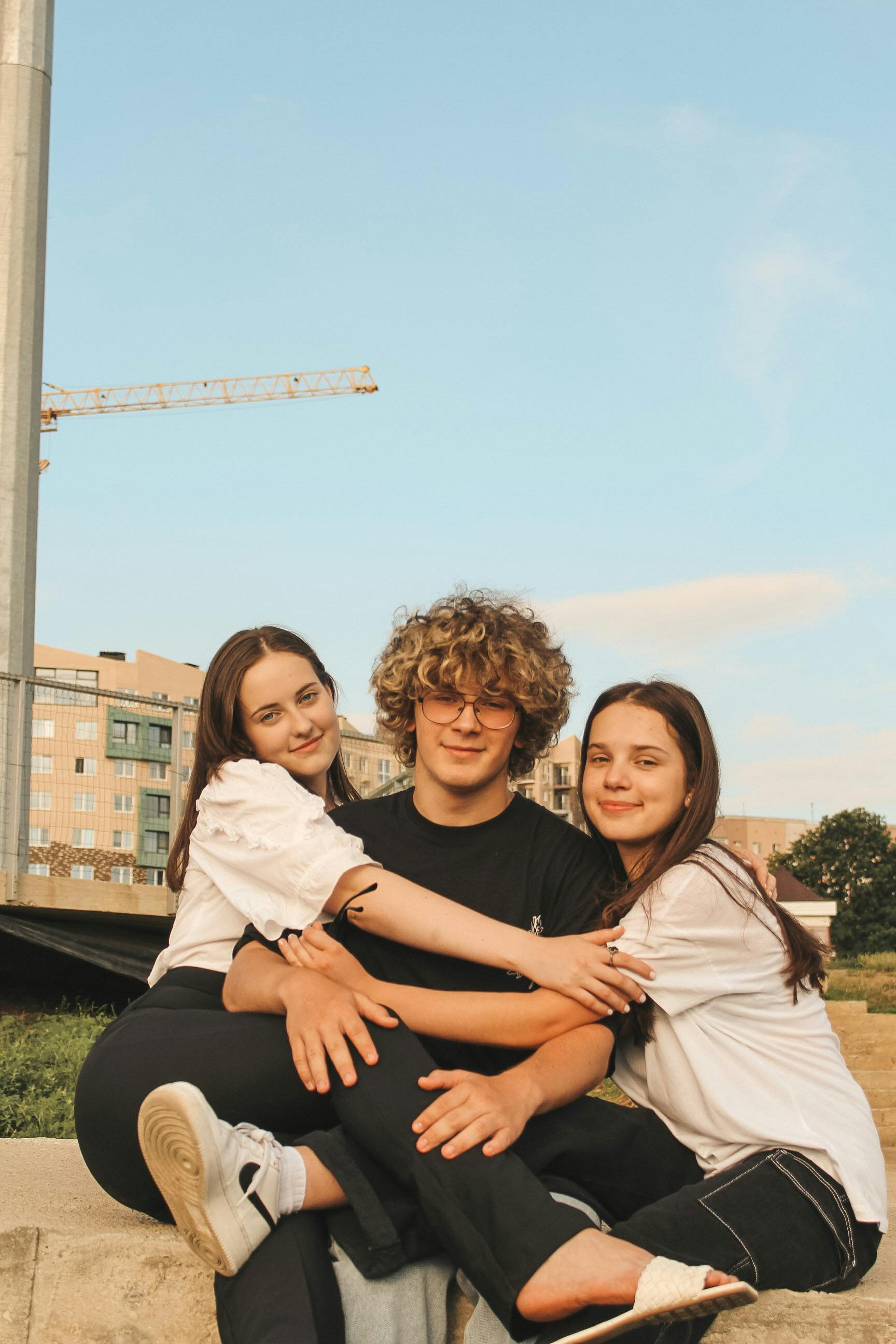 Friends Sitting Side by Side on Construction Site · Free Stock Photo
