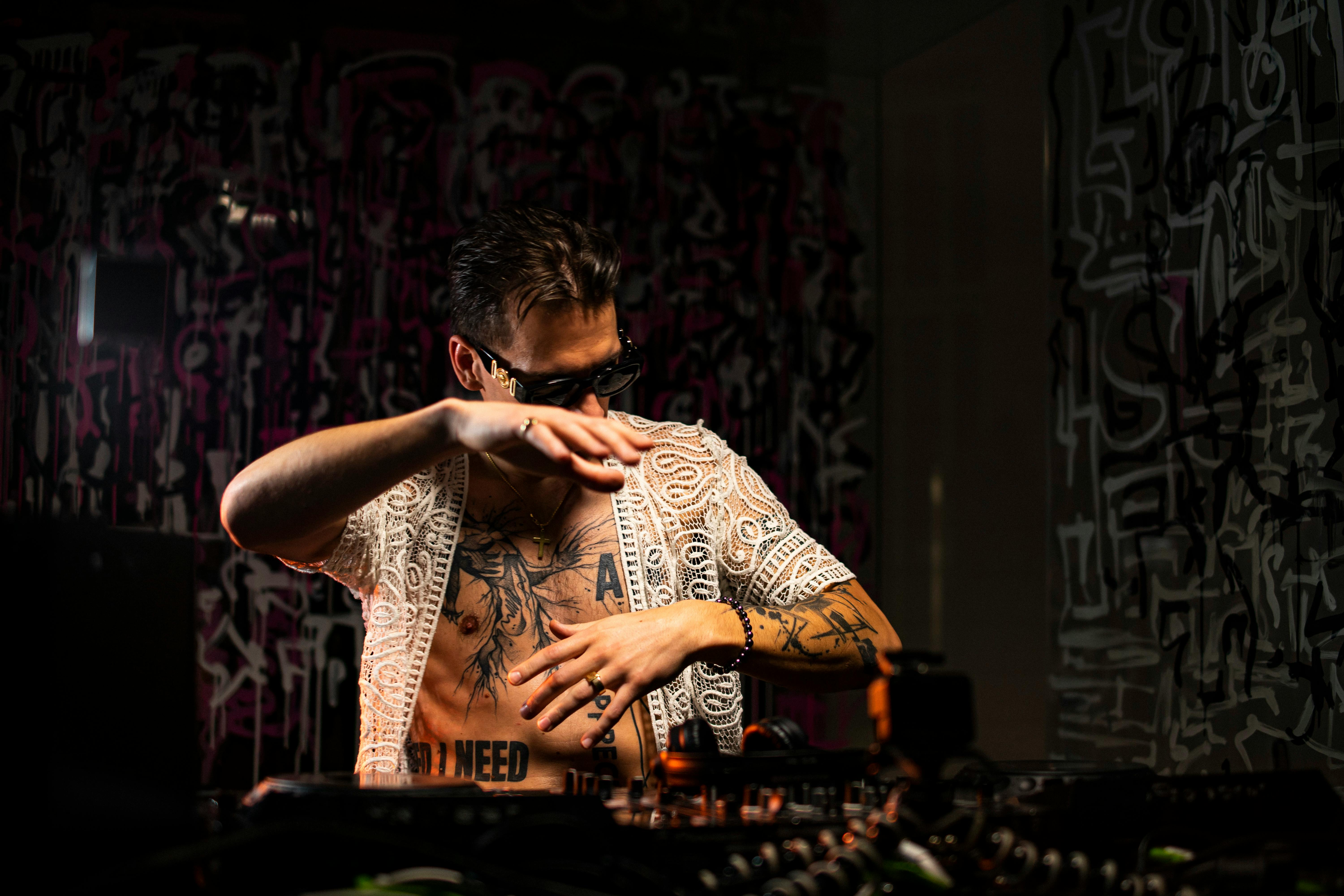 A Tattooed DJ Using a Mixer in a Nightclub · Free Stock Photo