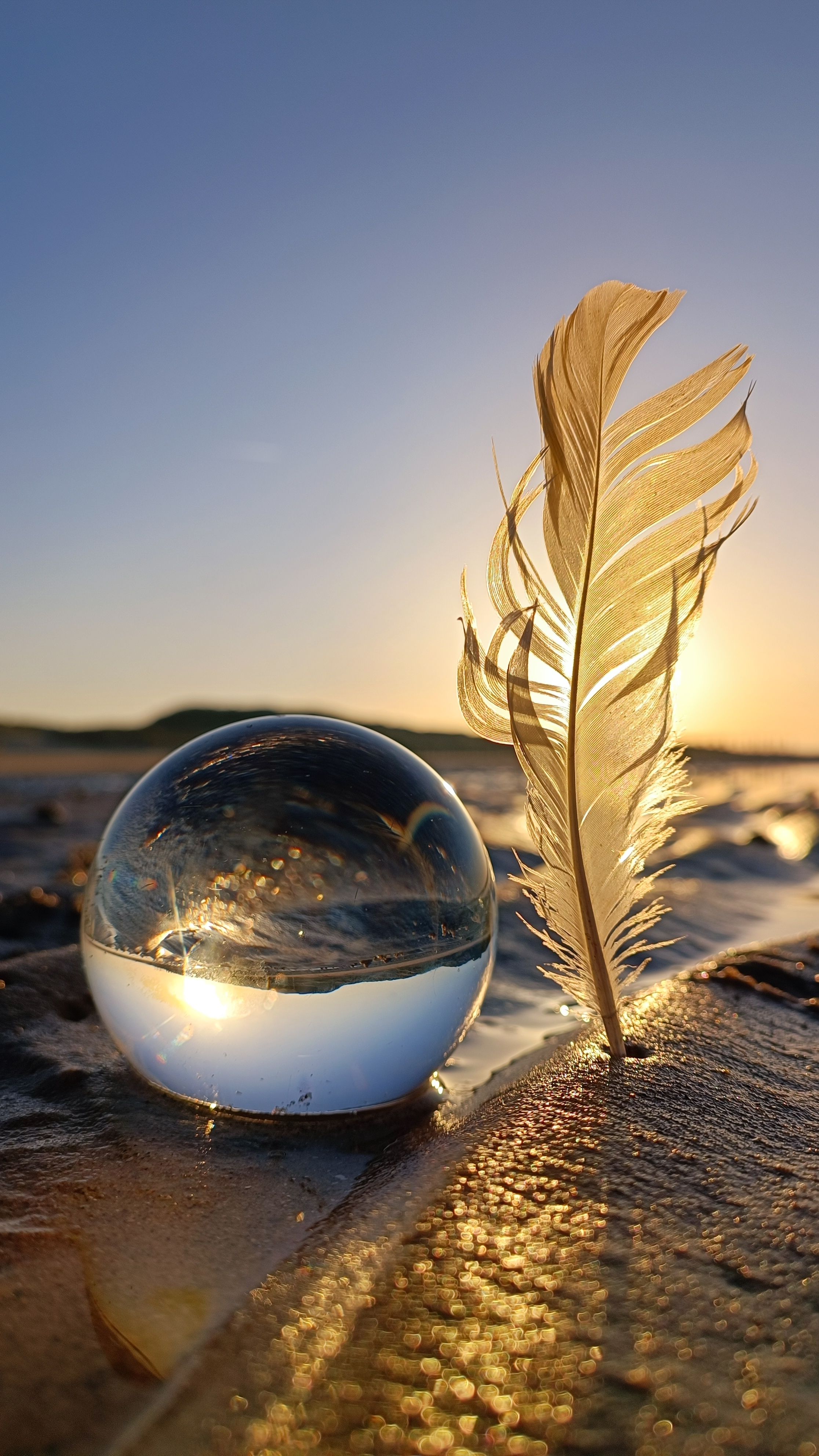 Glass Ball and Feather on a Beach · Free Stock Photo