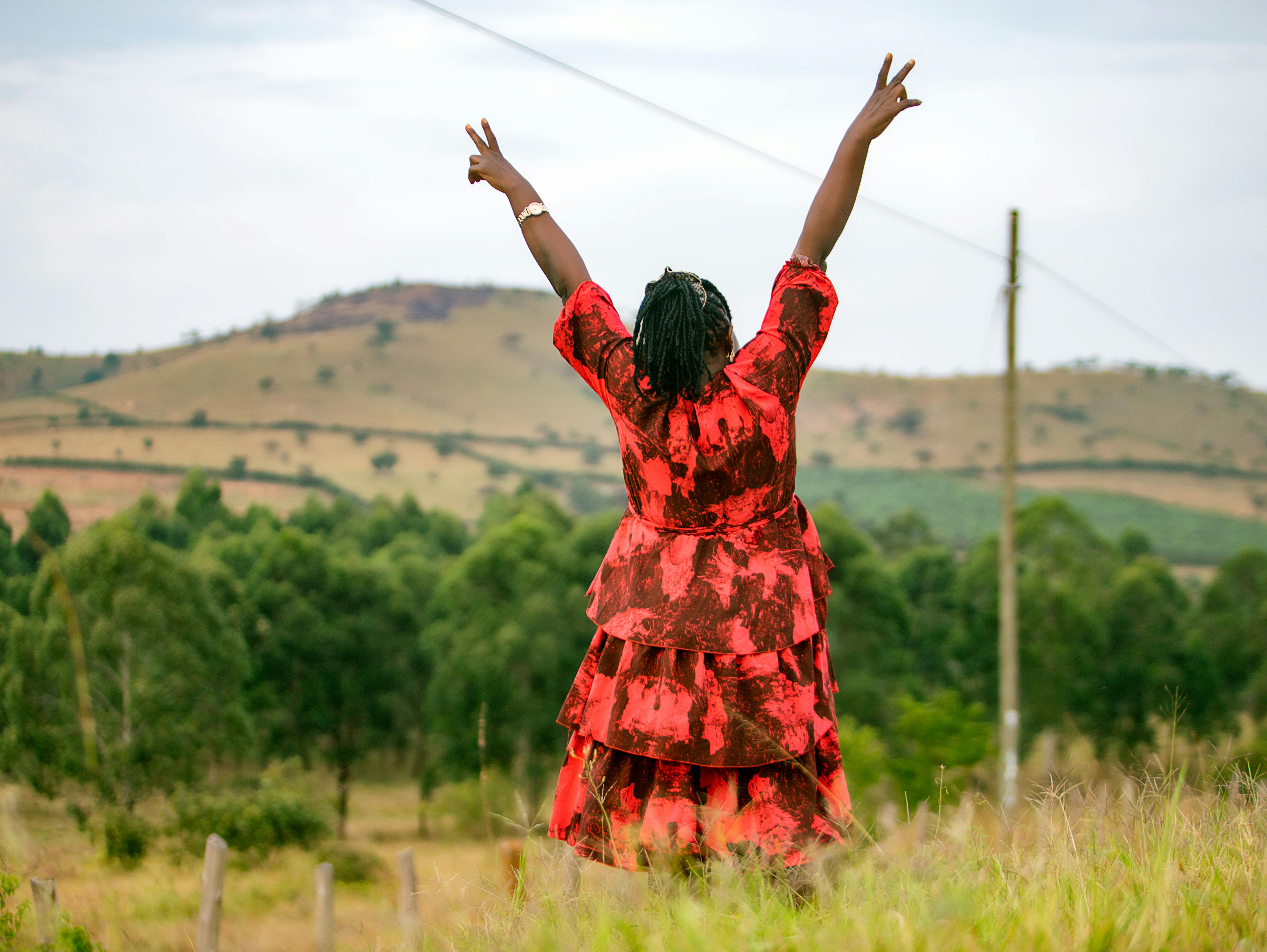 Woman Standing with Arms Raised on Grassland · Free Stock Photo