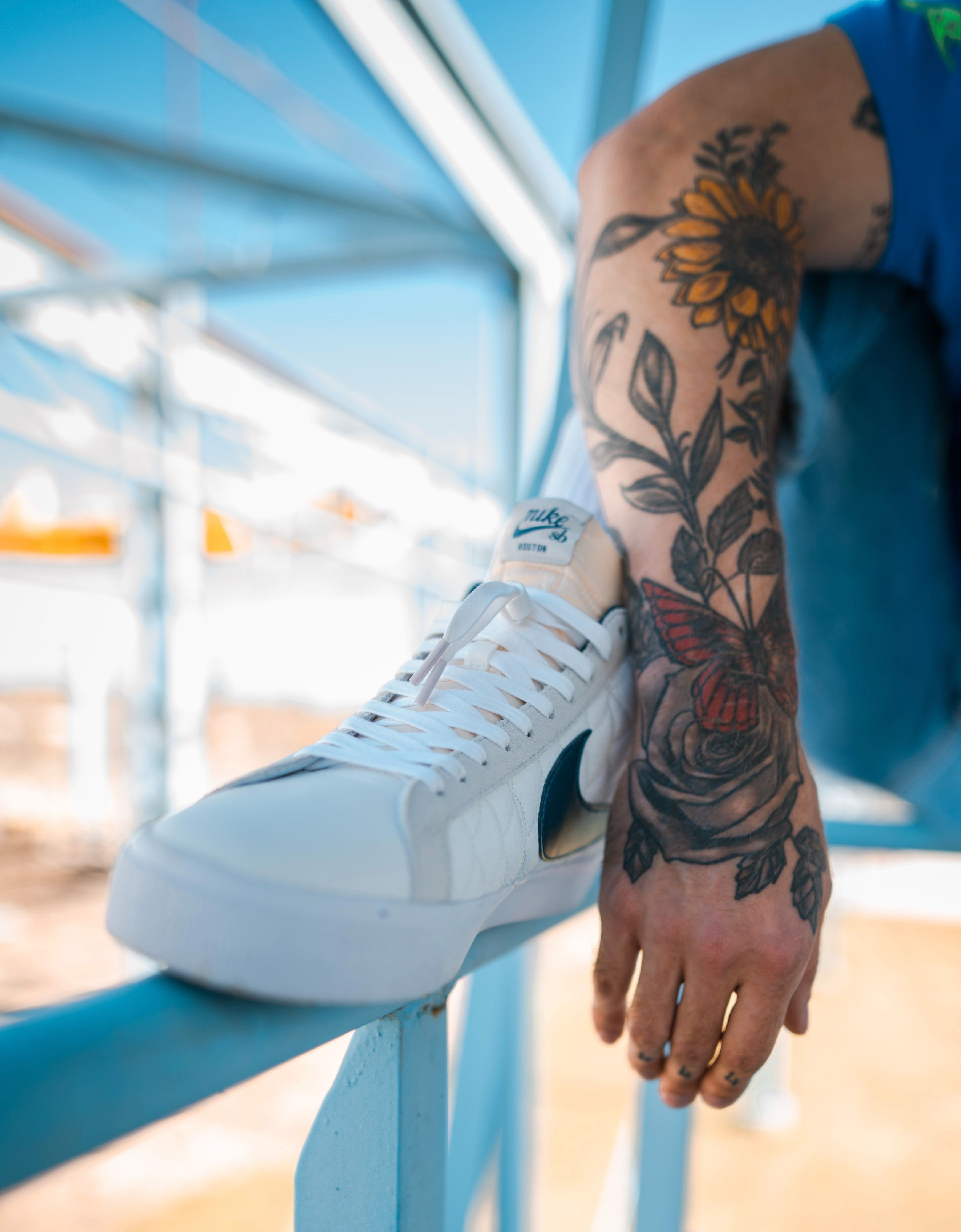 Man Arm with Tattoos over Shoe on Railing · Free Stock Photo