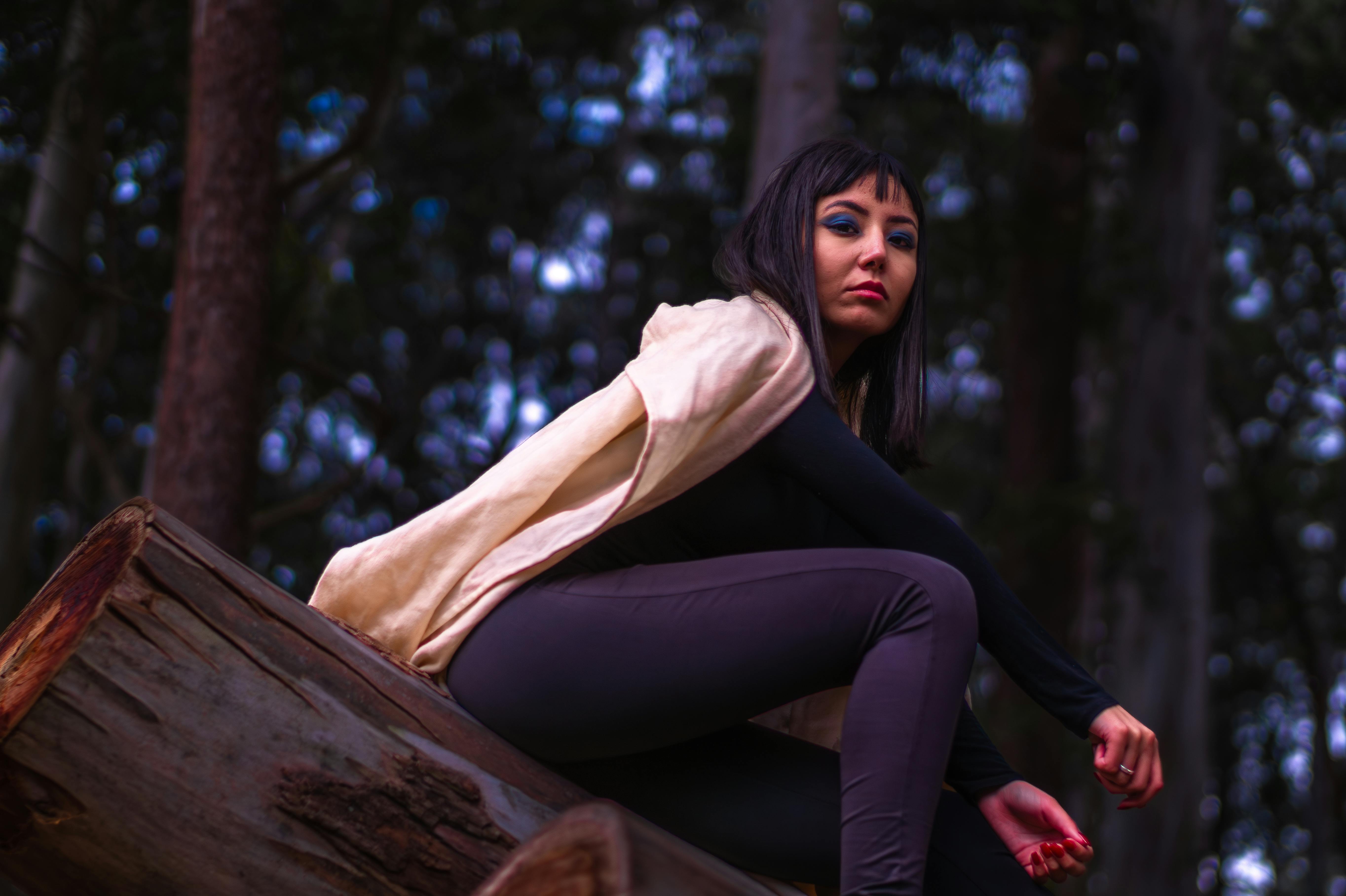 Woman in White Jacket Sitting on Pile of Firewood · Free Stock Photo