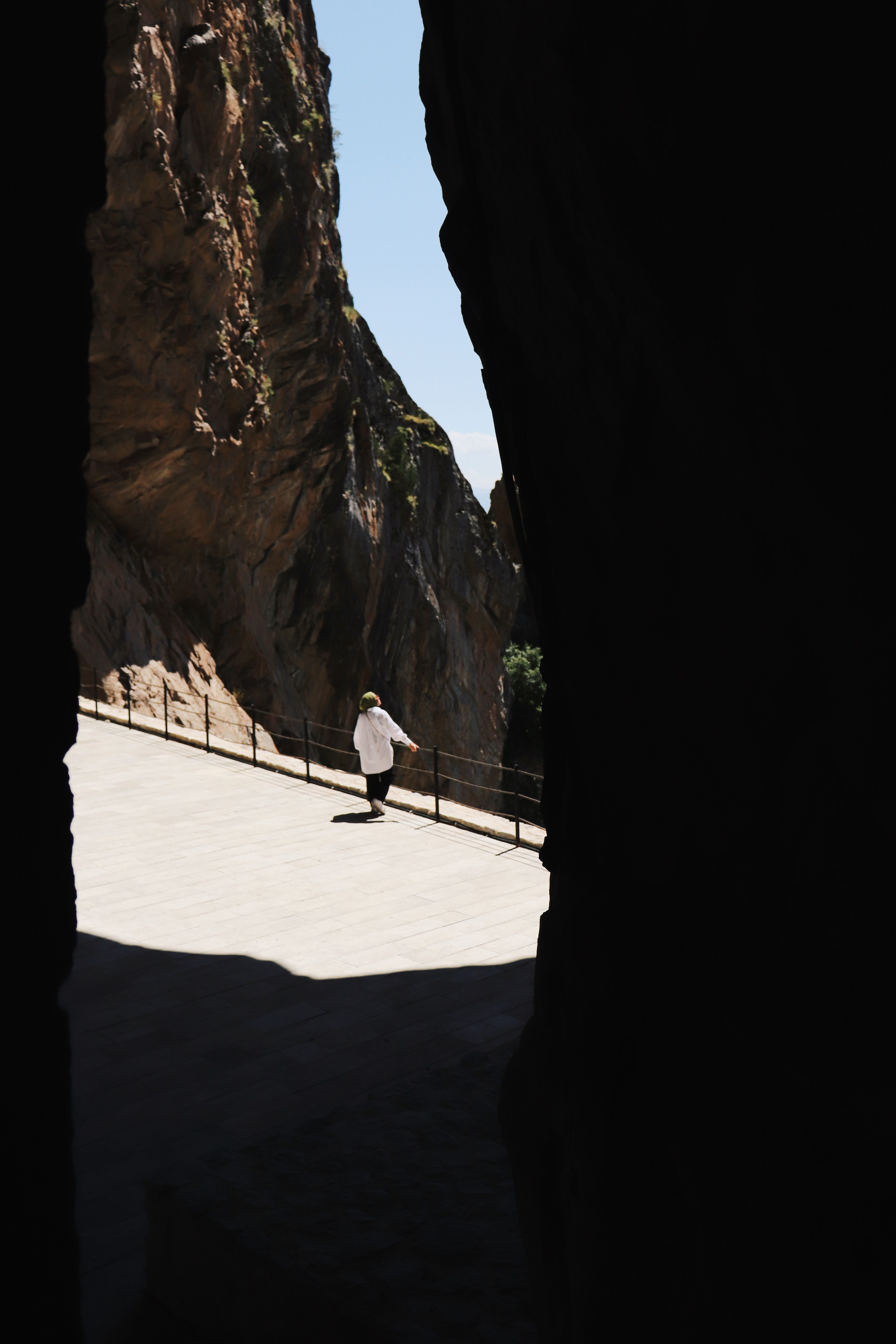 Woman on Sunlit Pavement behind Rock Formations · Free Stock Photo