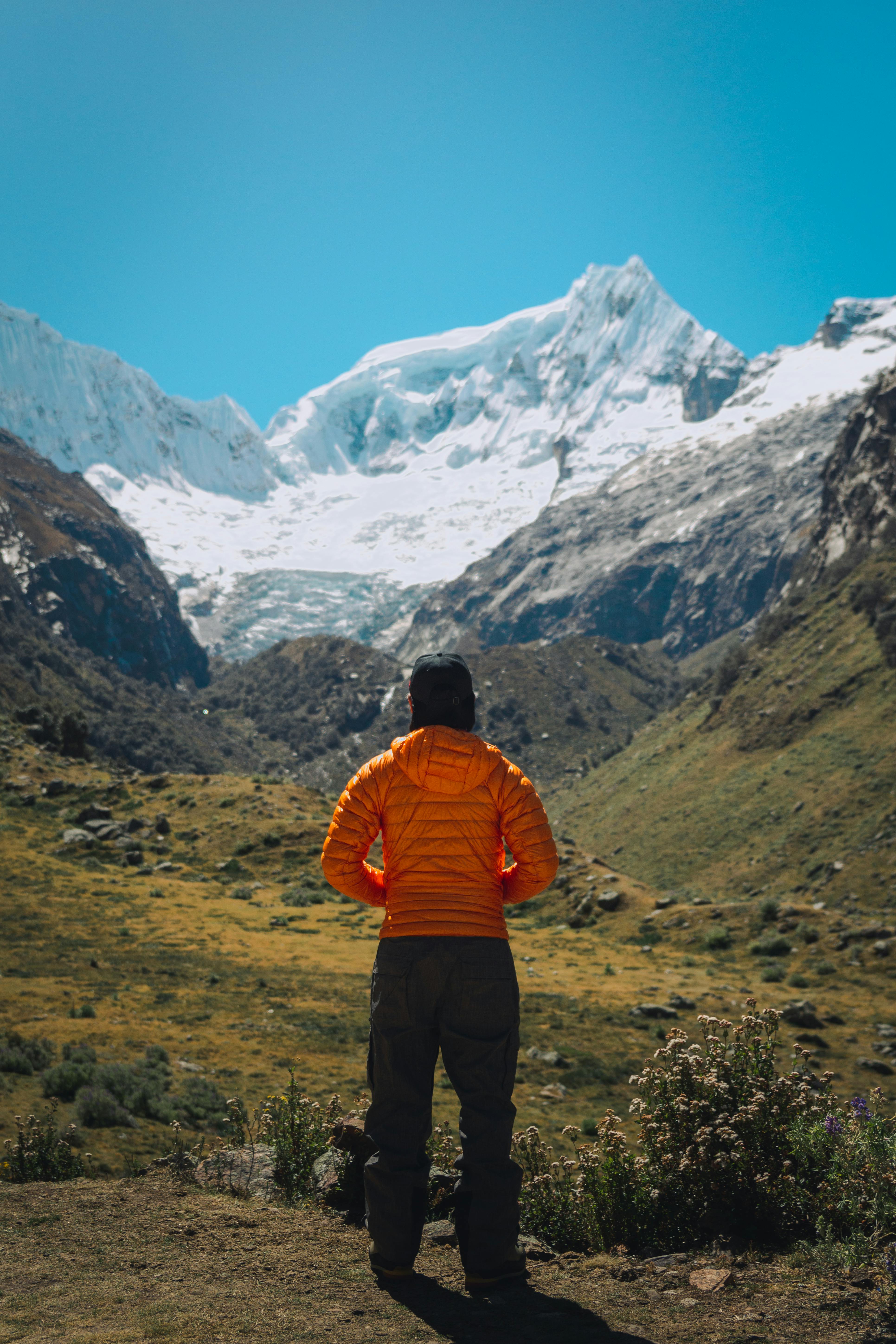 Person in Orange Puffer Jacket Enjoying a Scenic Mountain Landscape ...