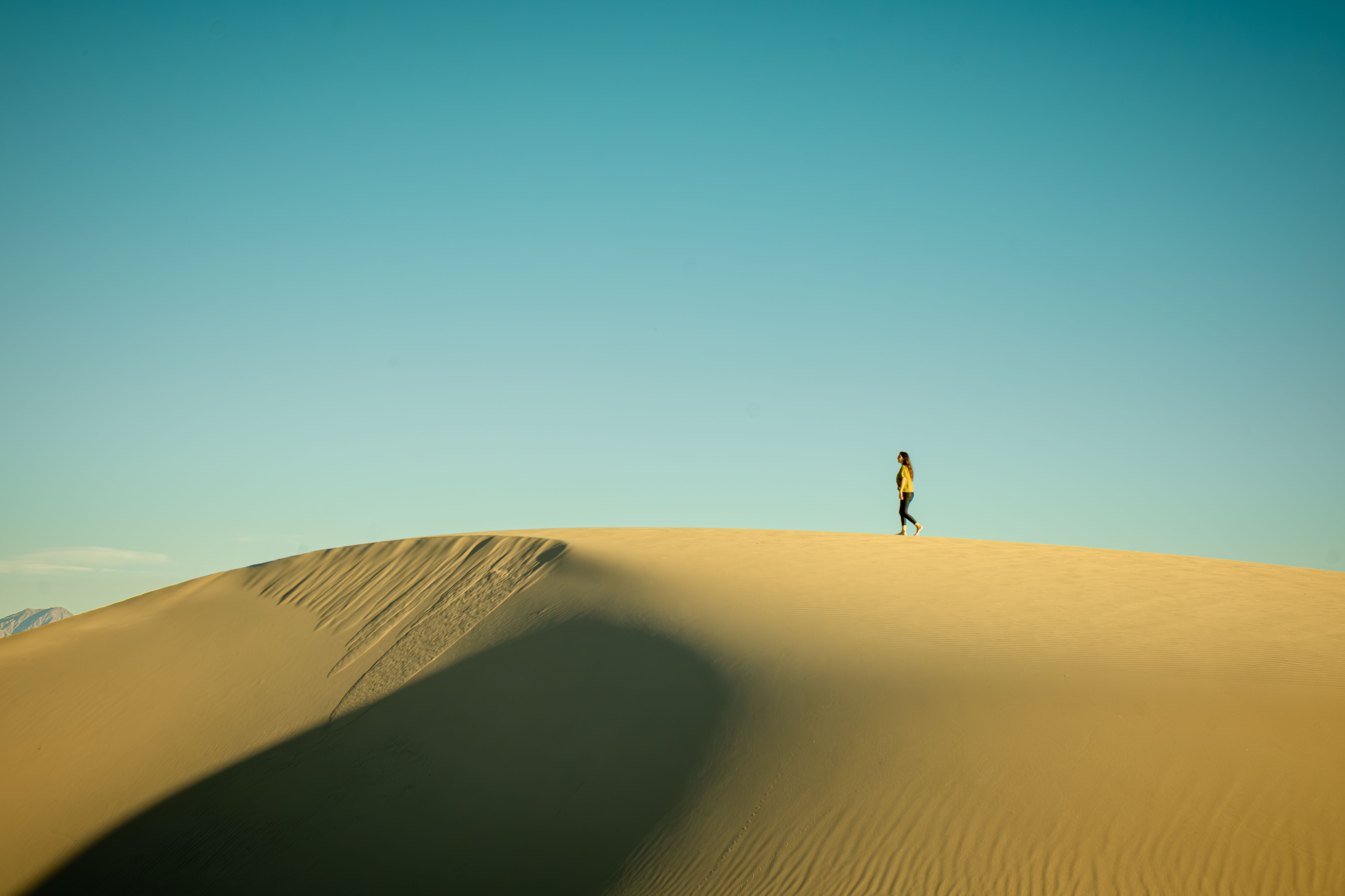 Woman Walking across Sand Dunes under Blue Sky · Free Stock Photo