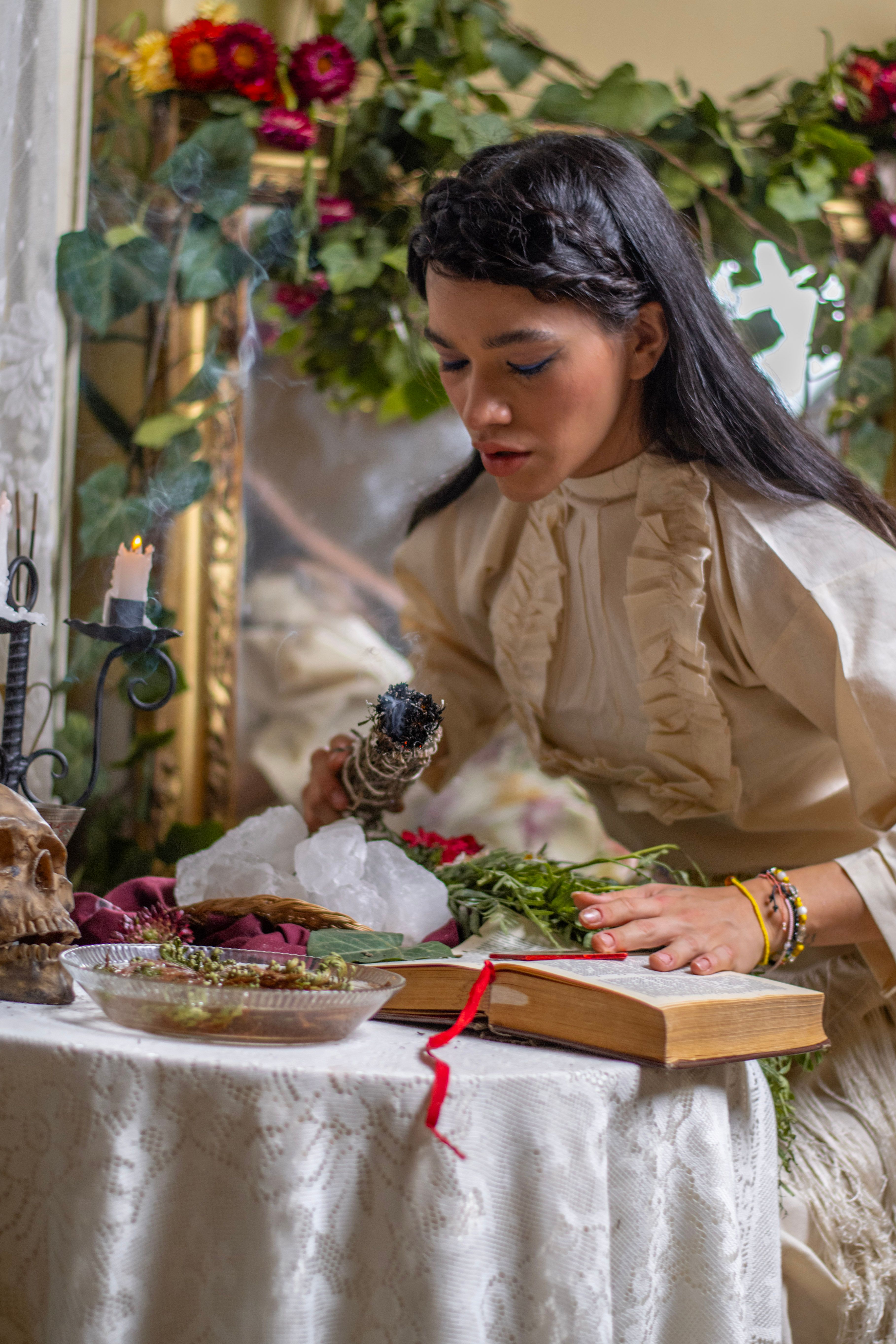 Woman in a Dress Sitting by a Table and Holding a Sage Bundle · Free ...