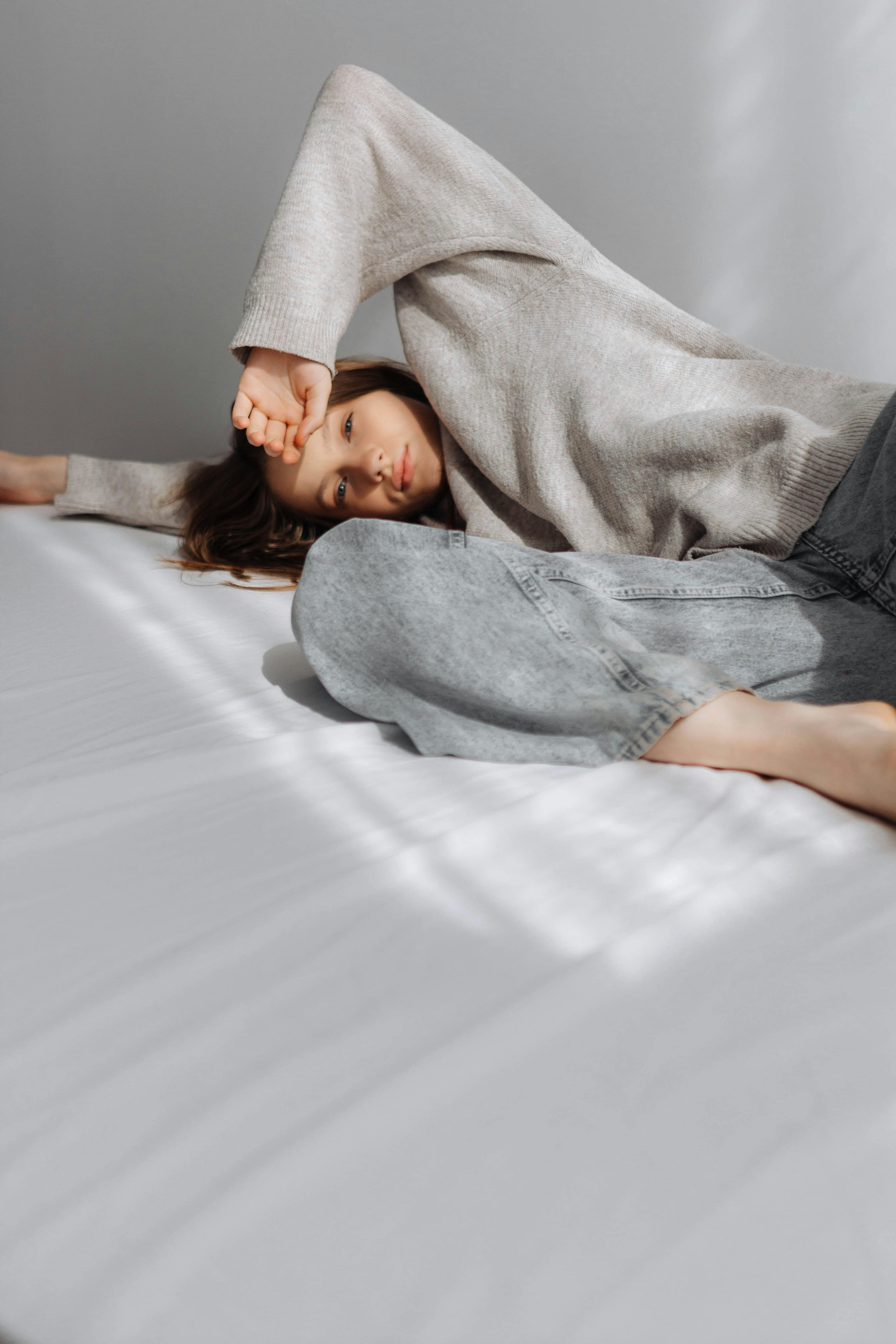 Studio Shot of a Young Girl in a Simple Outfit Sitting on a Mattress on ...