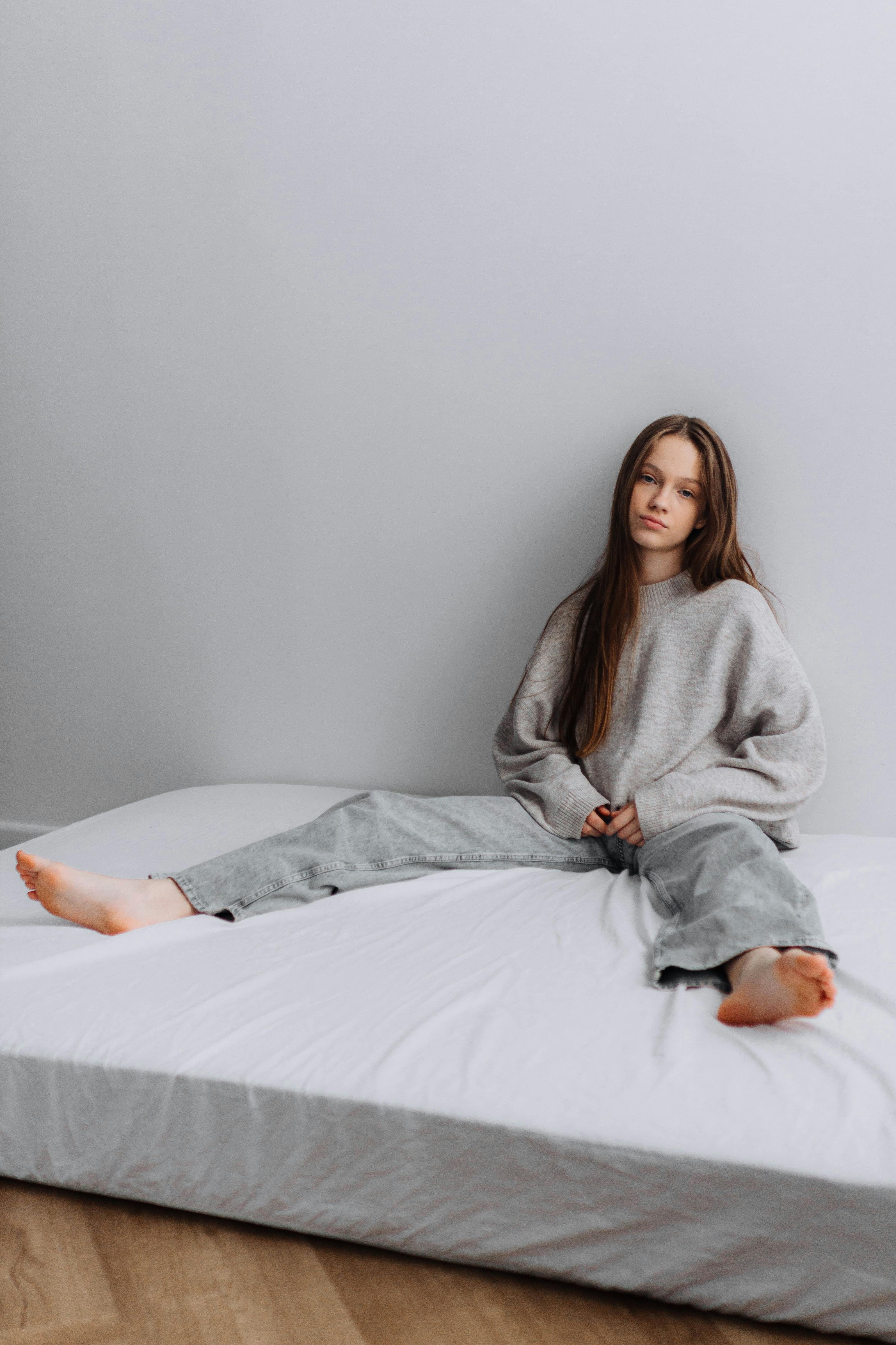 Studio Shot of a Young Girl in a Simple Outfit Sitting on a Mattress on ...