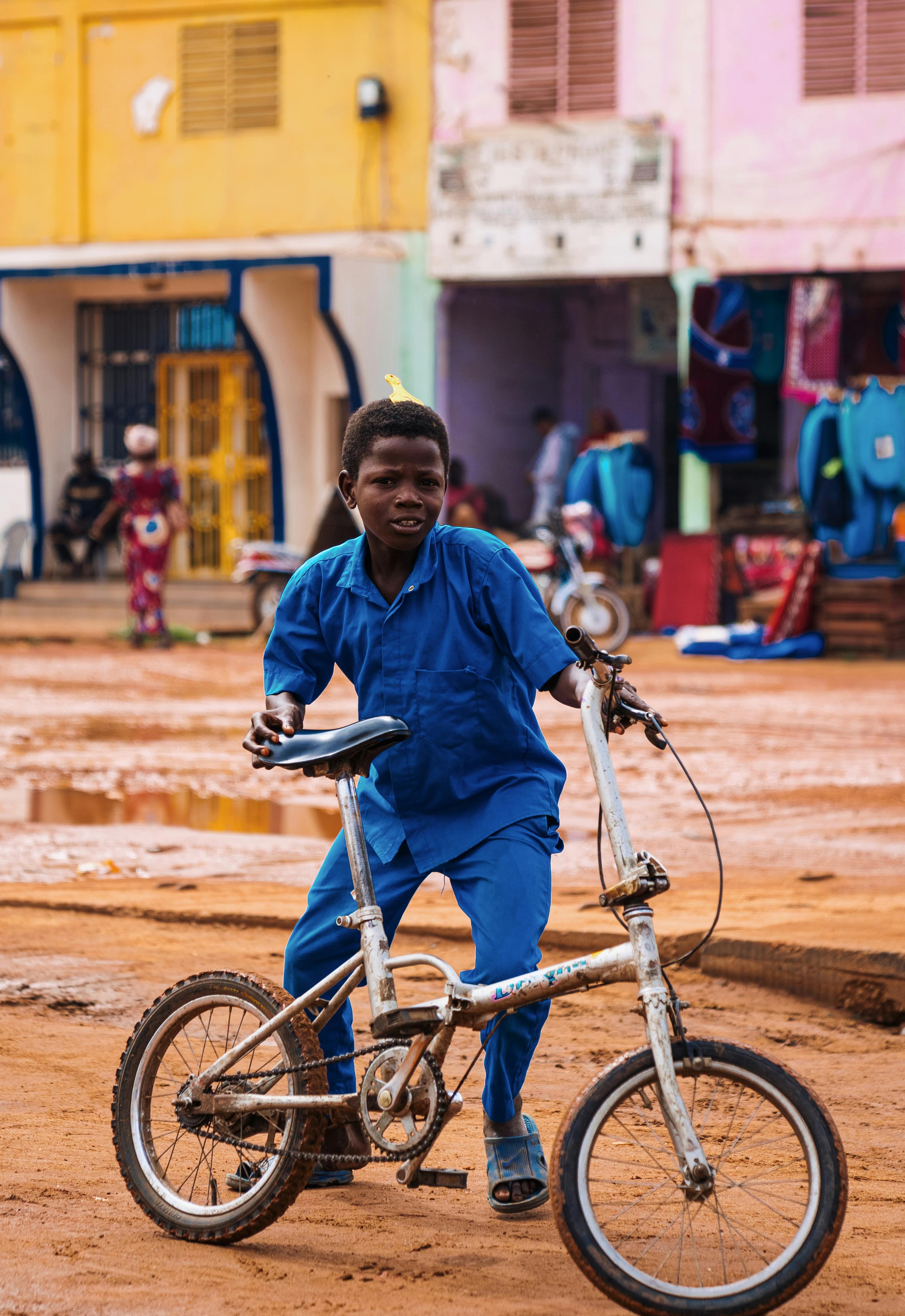 Boy Holding a Bike on Muddy Street · Free Stock Photo