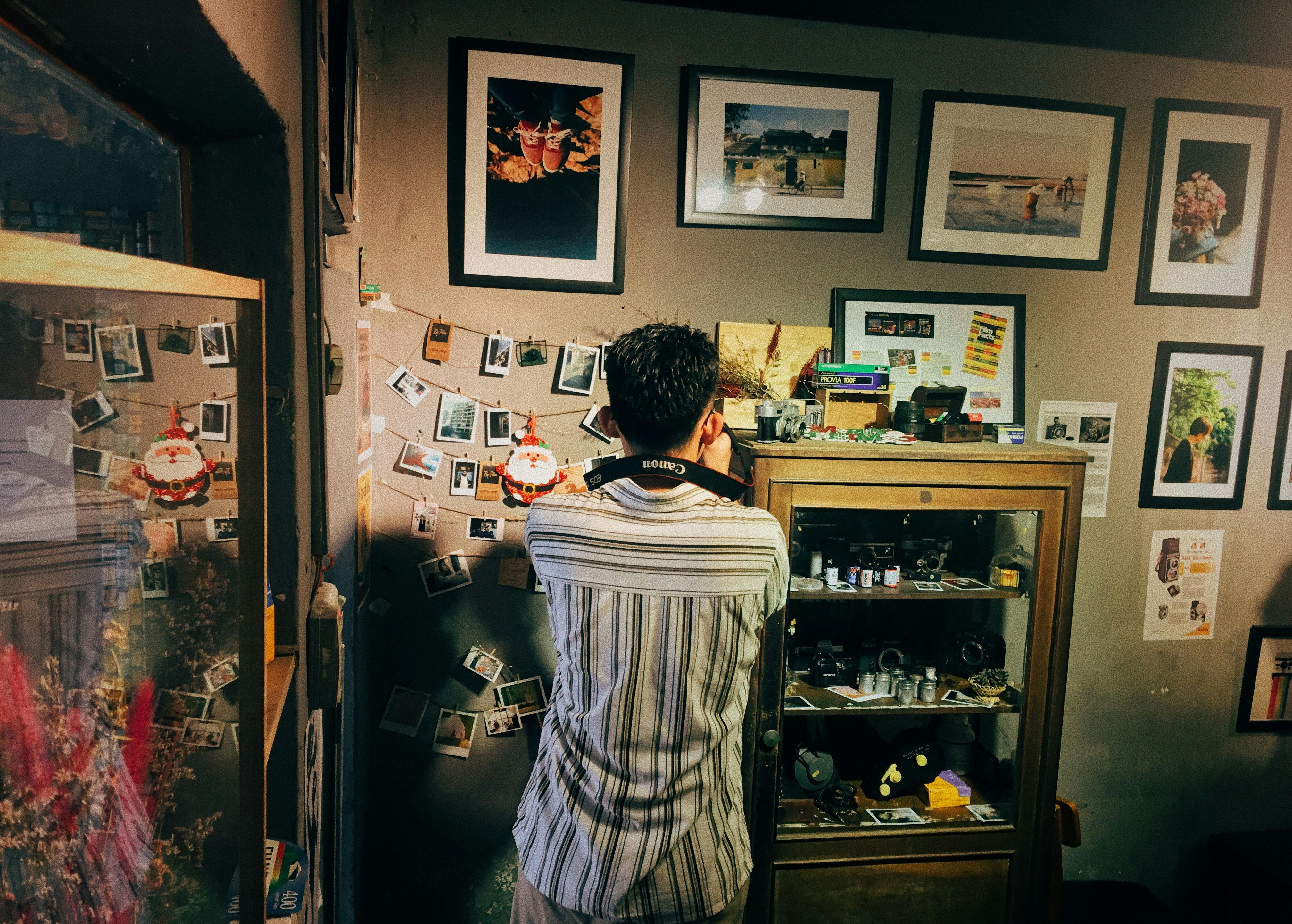 Man Facing Photos Attached on Wall · Free Stock Photo