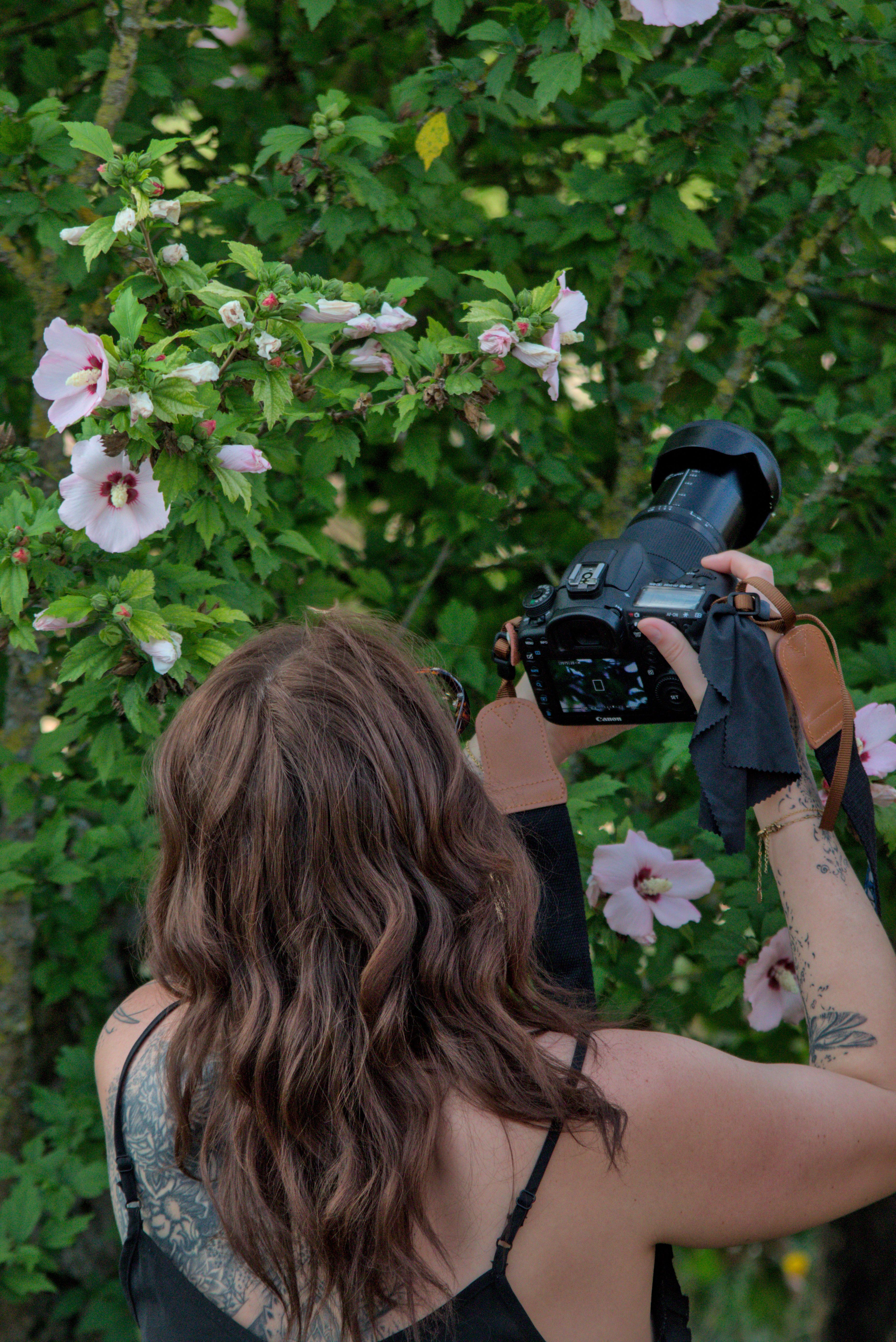 Woman with Tattoos Taking Pictures of Flowers · Free Stock Photo