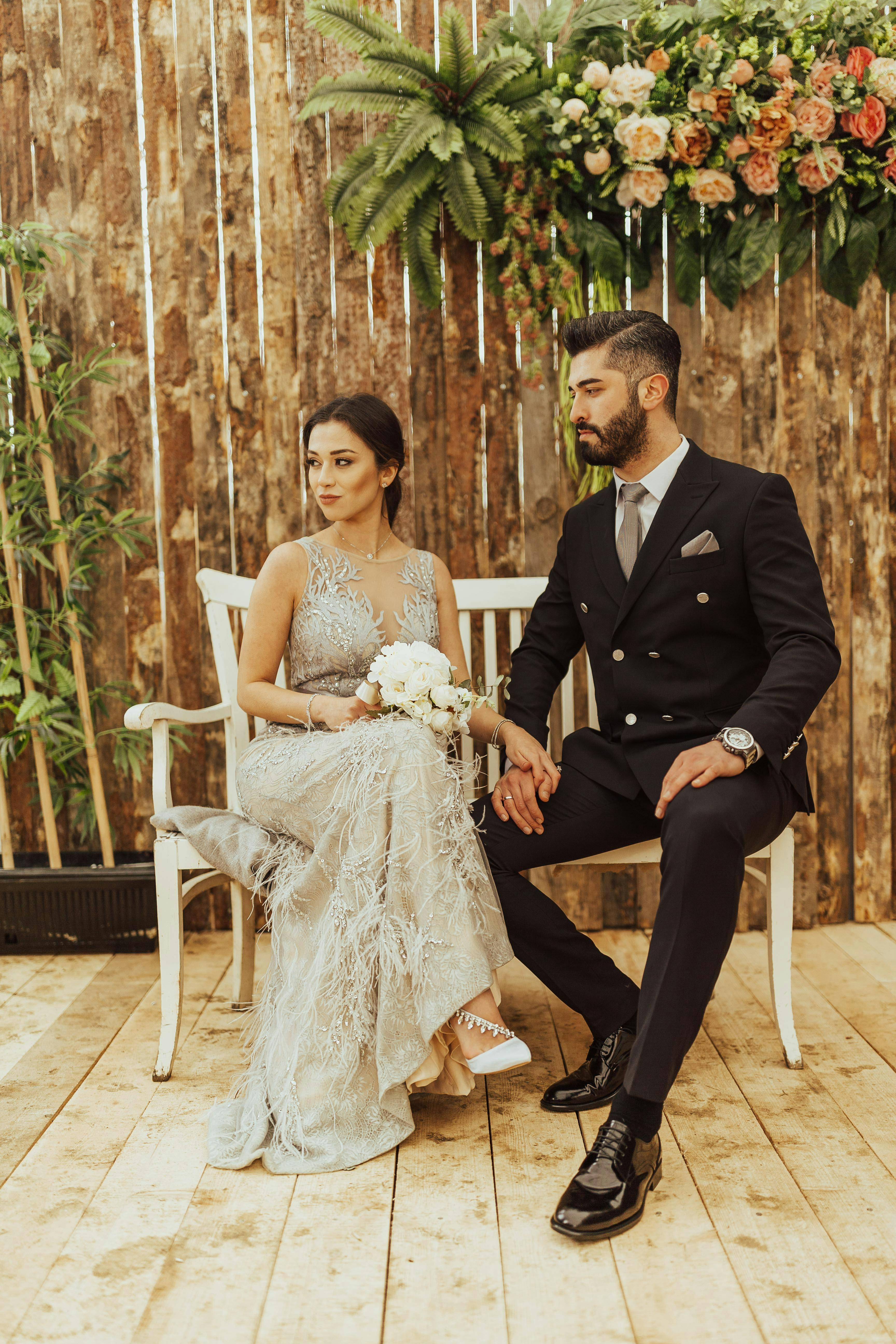 Bride and Groom Sitting Together on White Bench · Free Stock Photo