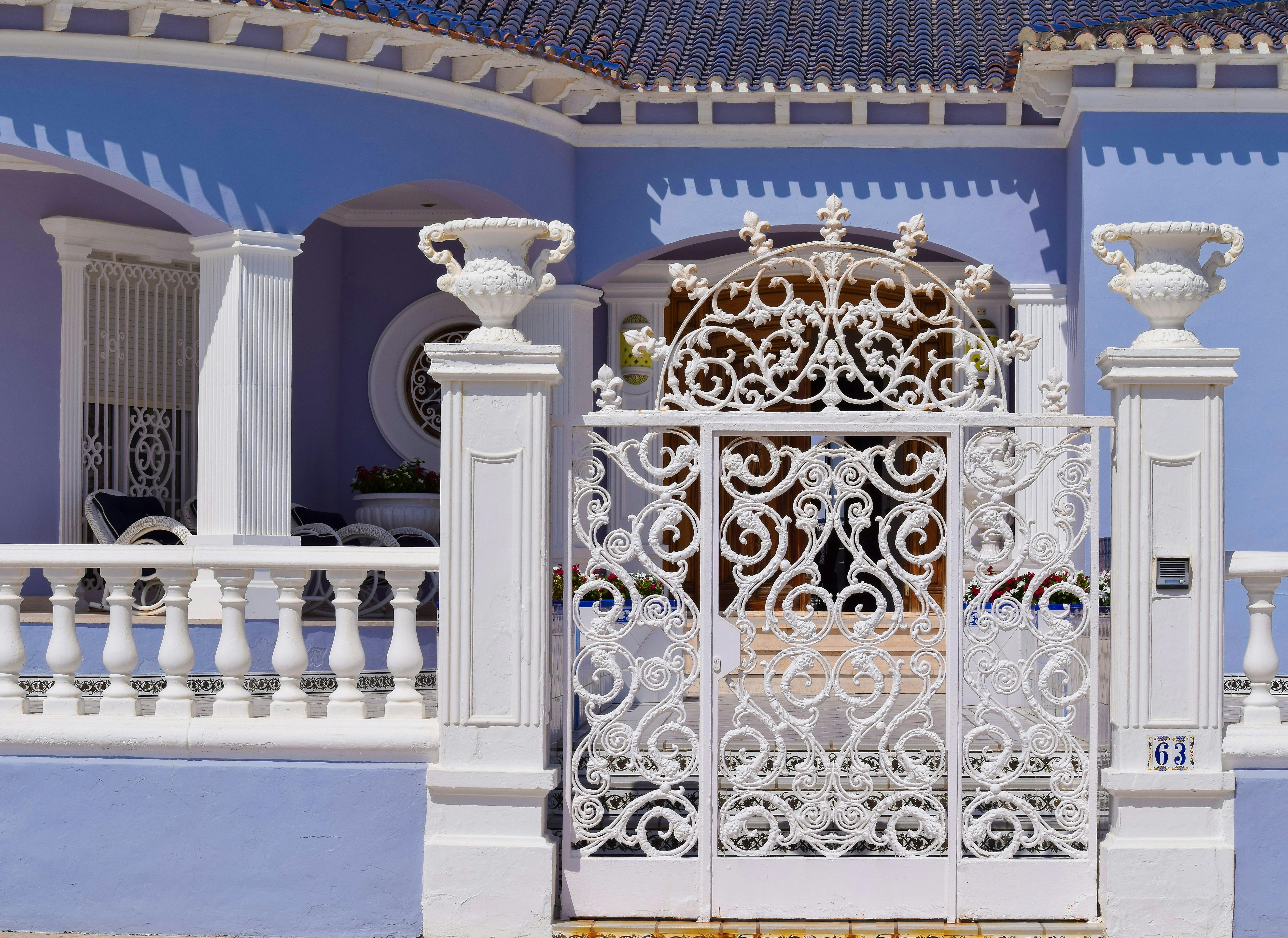 A Blue Mansion and a White Fence with Artistic Design · Free Stock Photo