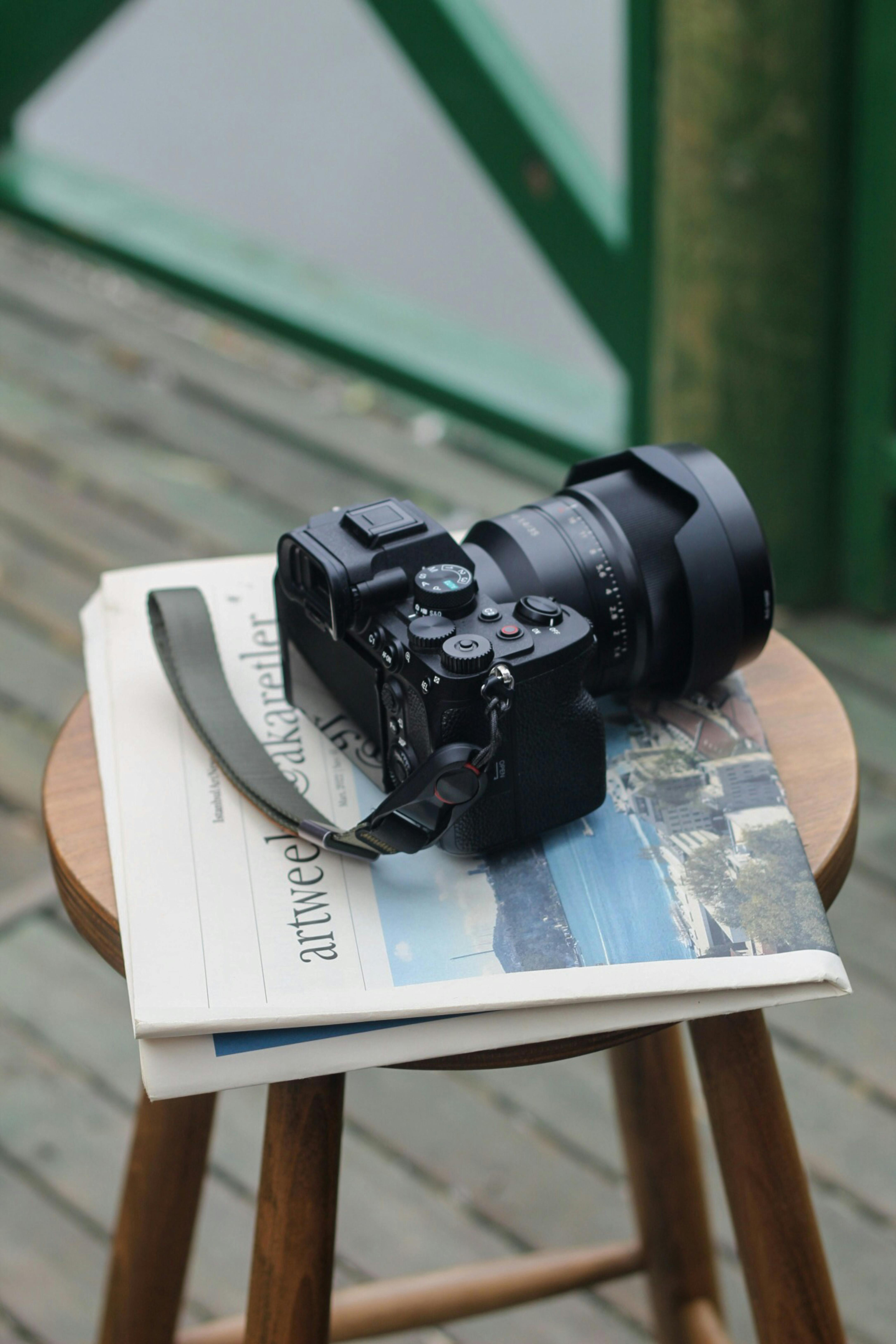 An SLR Camera Lying on a Stool with a Newspaper · Free Stock Photo