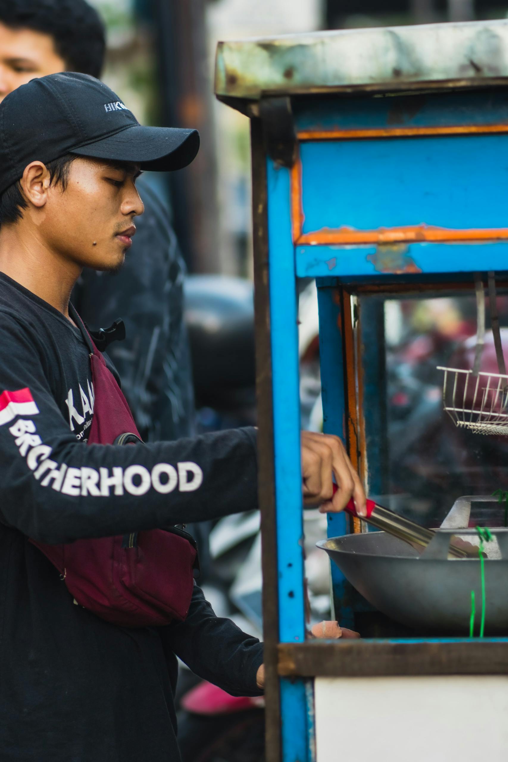 Man in Cap Working on Food Stand · Free Stock Photo